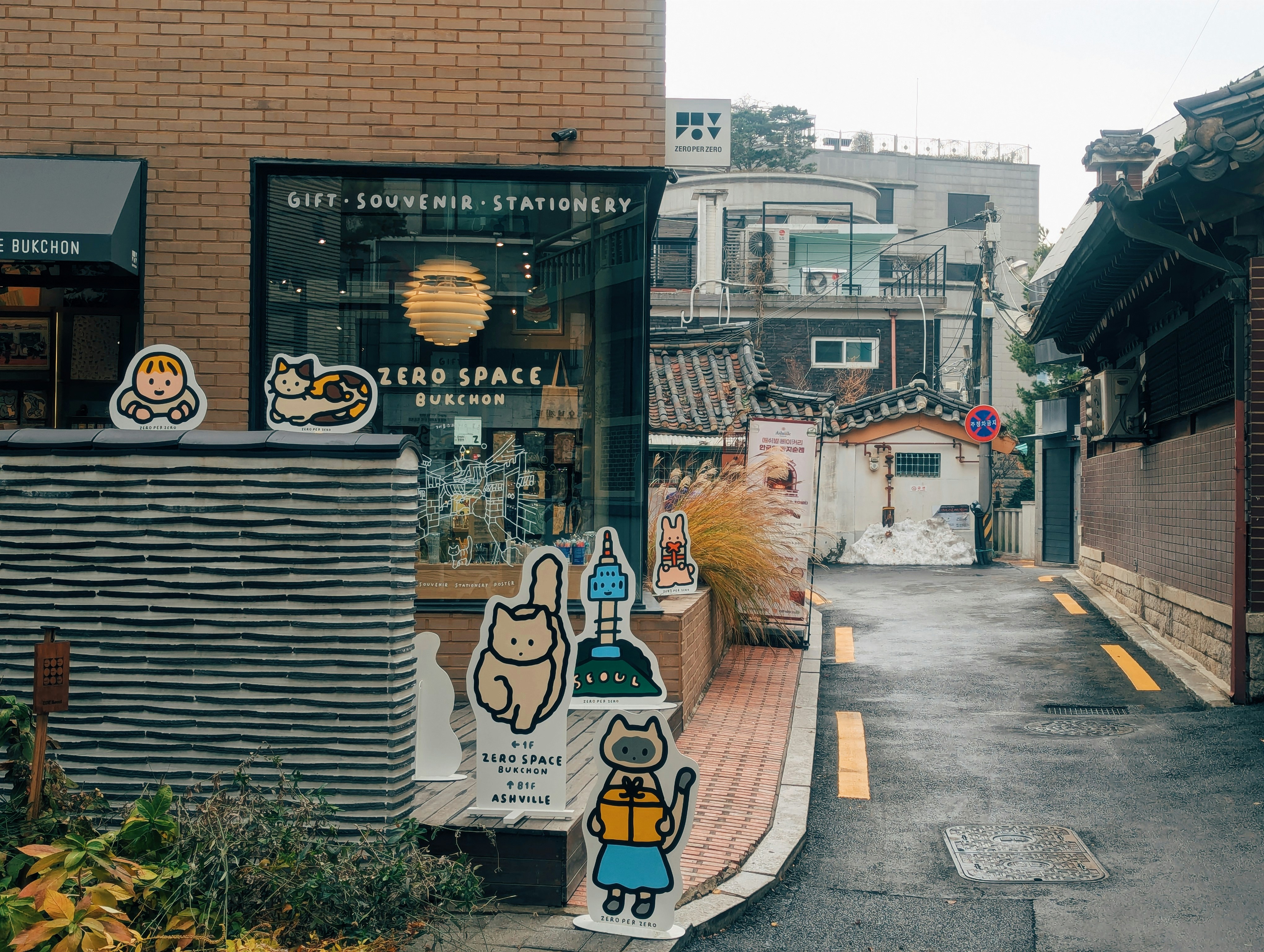 Colorful cartoon characters adorn a quaint shop facade next to a narrow urban alley.