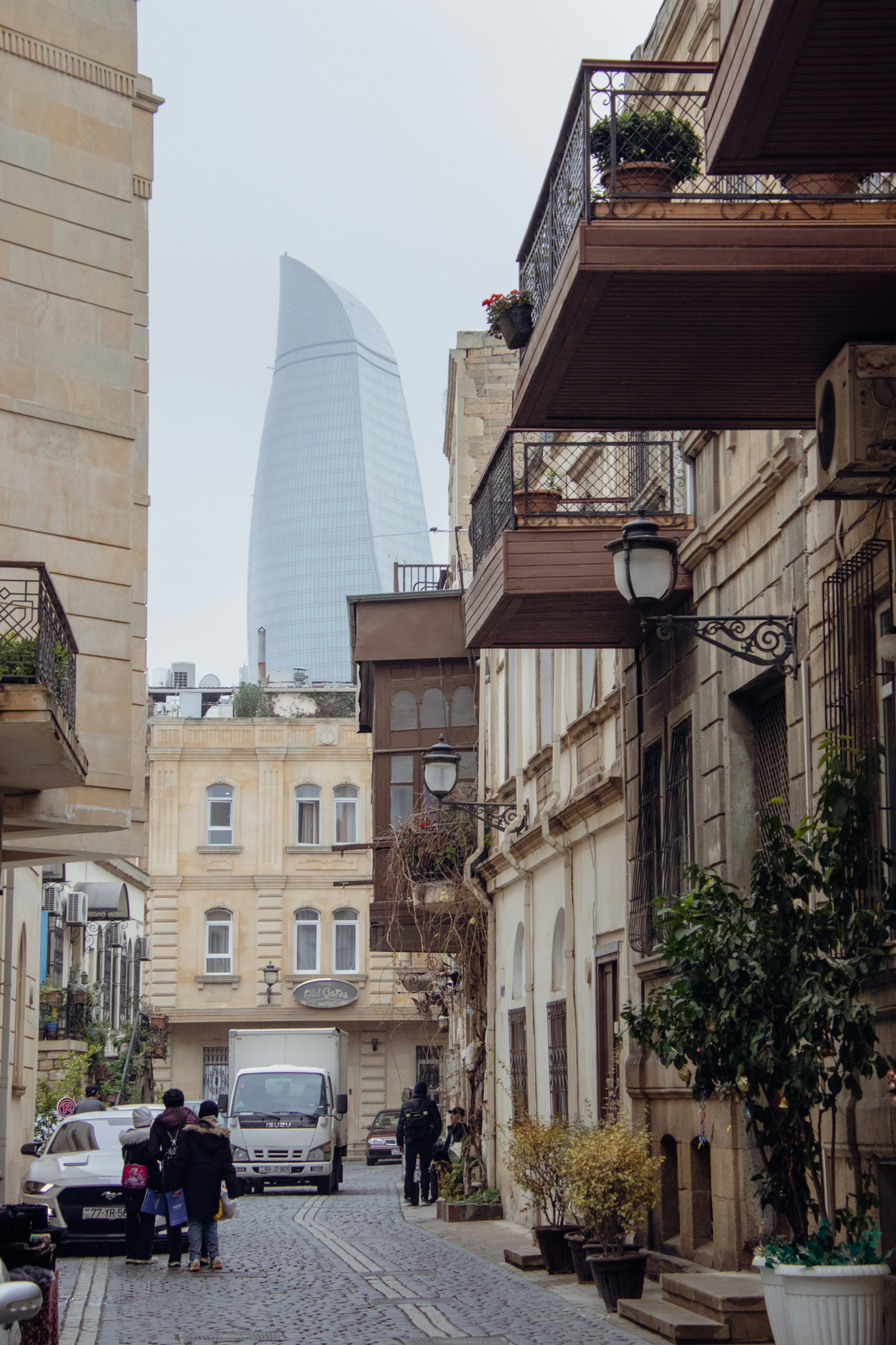 Sail and Stone: Narrow Street Framing a Modern Needle