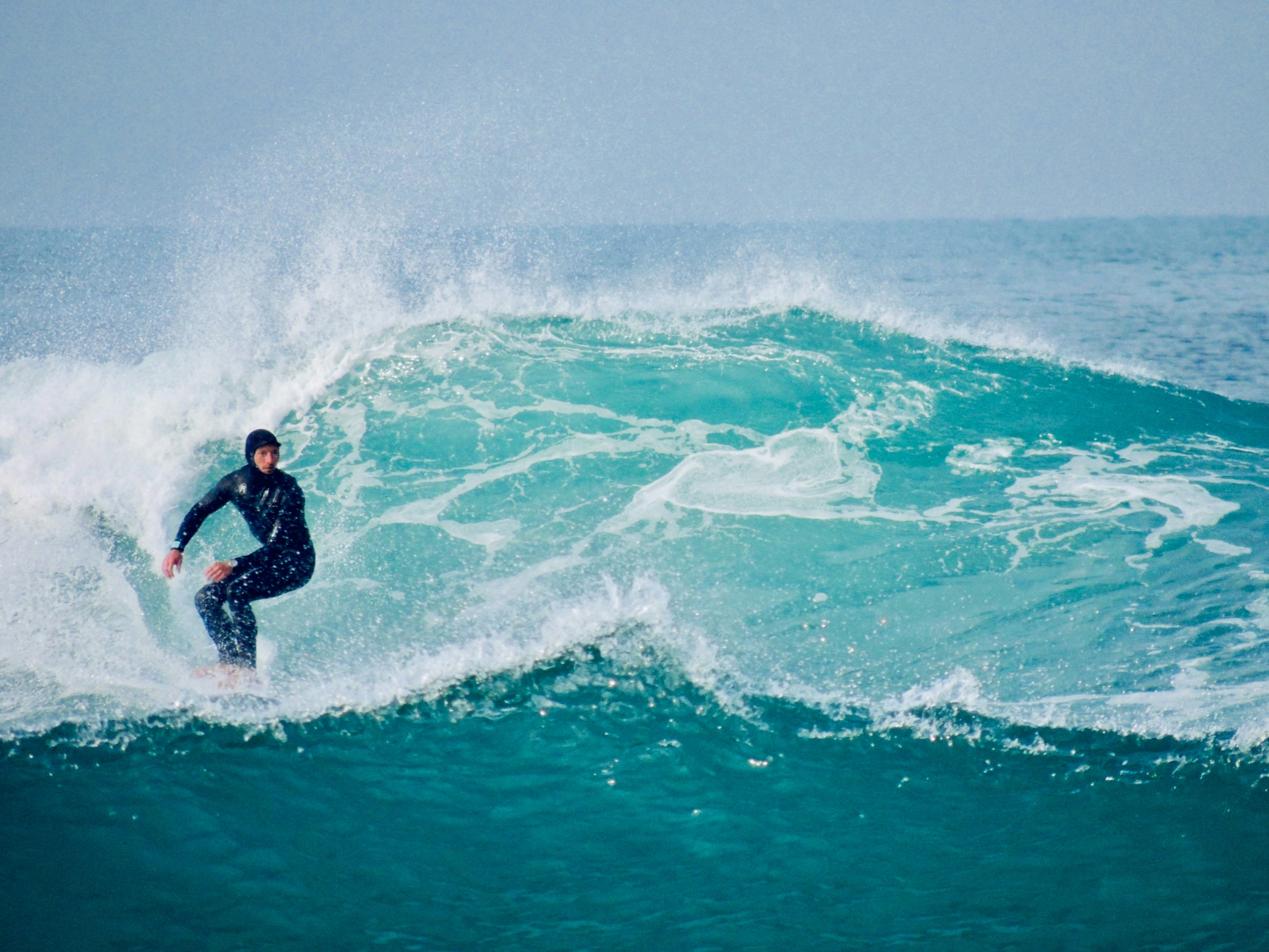 Teal Crest Rider: a surfer threads a curling turquoise wall