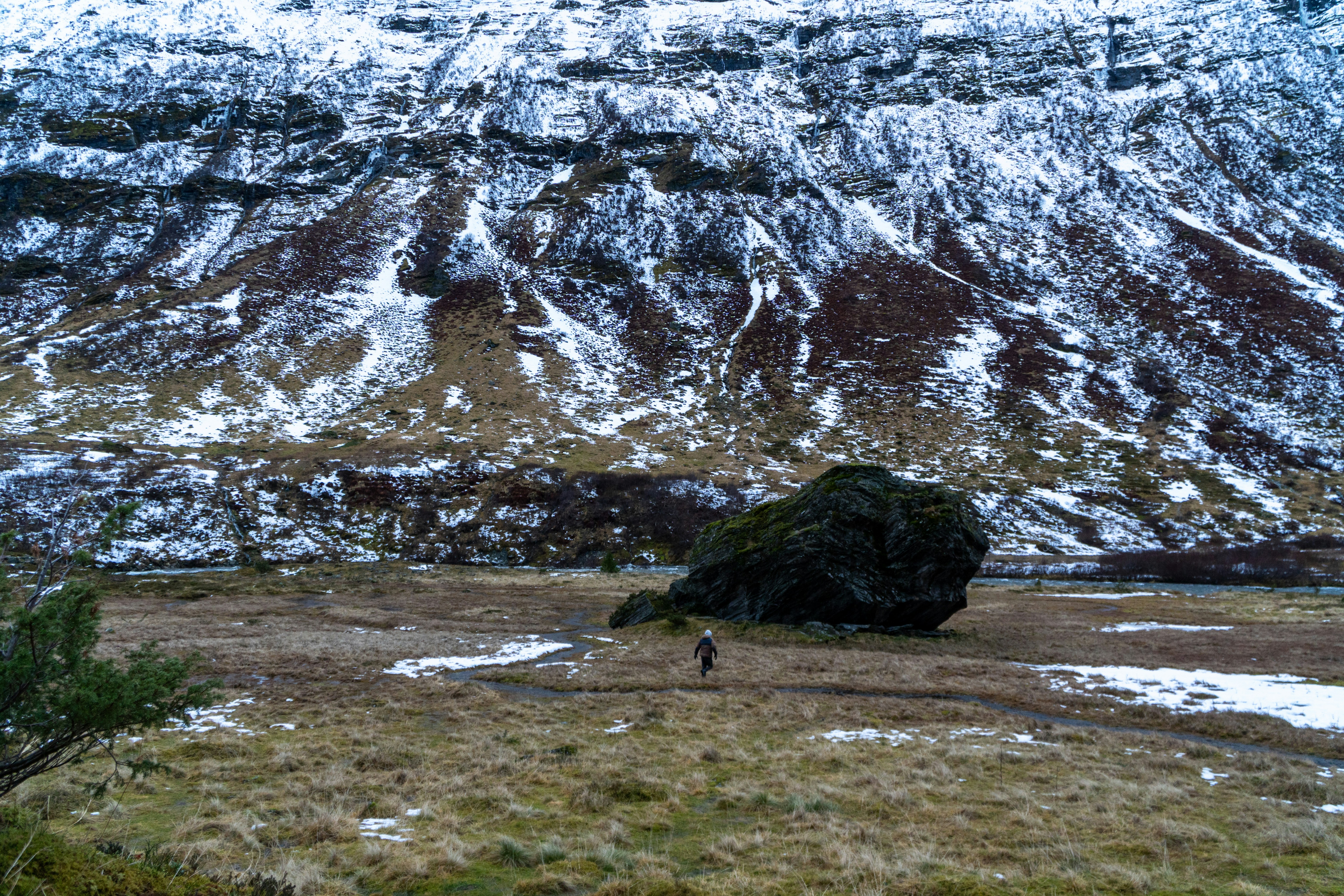 The Quiet Sentinel: Lone Wanderer at a Snow-Dusted Monolith