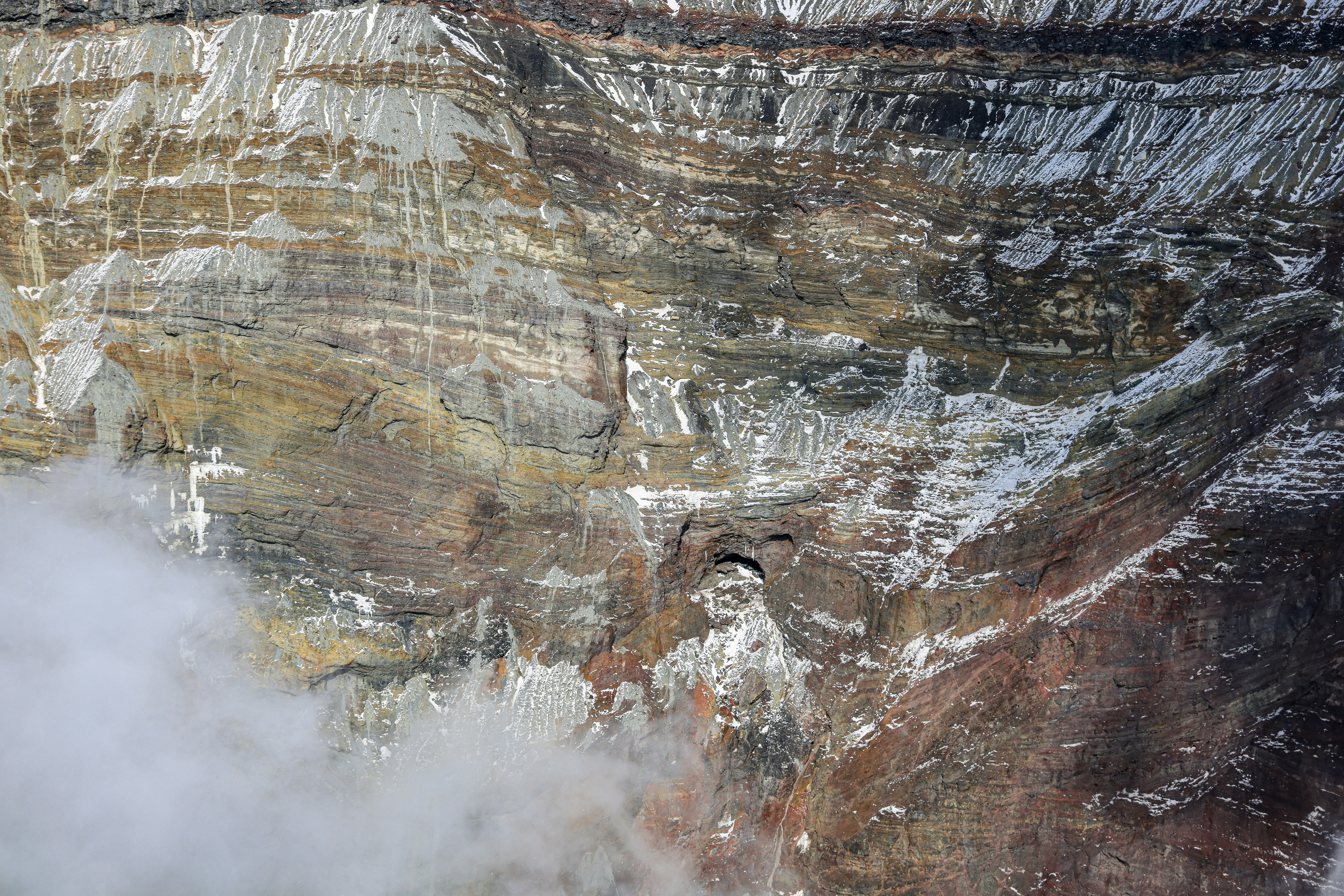 A mountain covered in snow and clouds next to a cliff photo – Free Rock ...