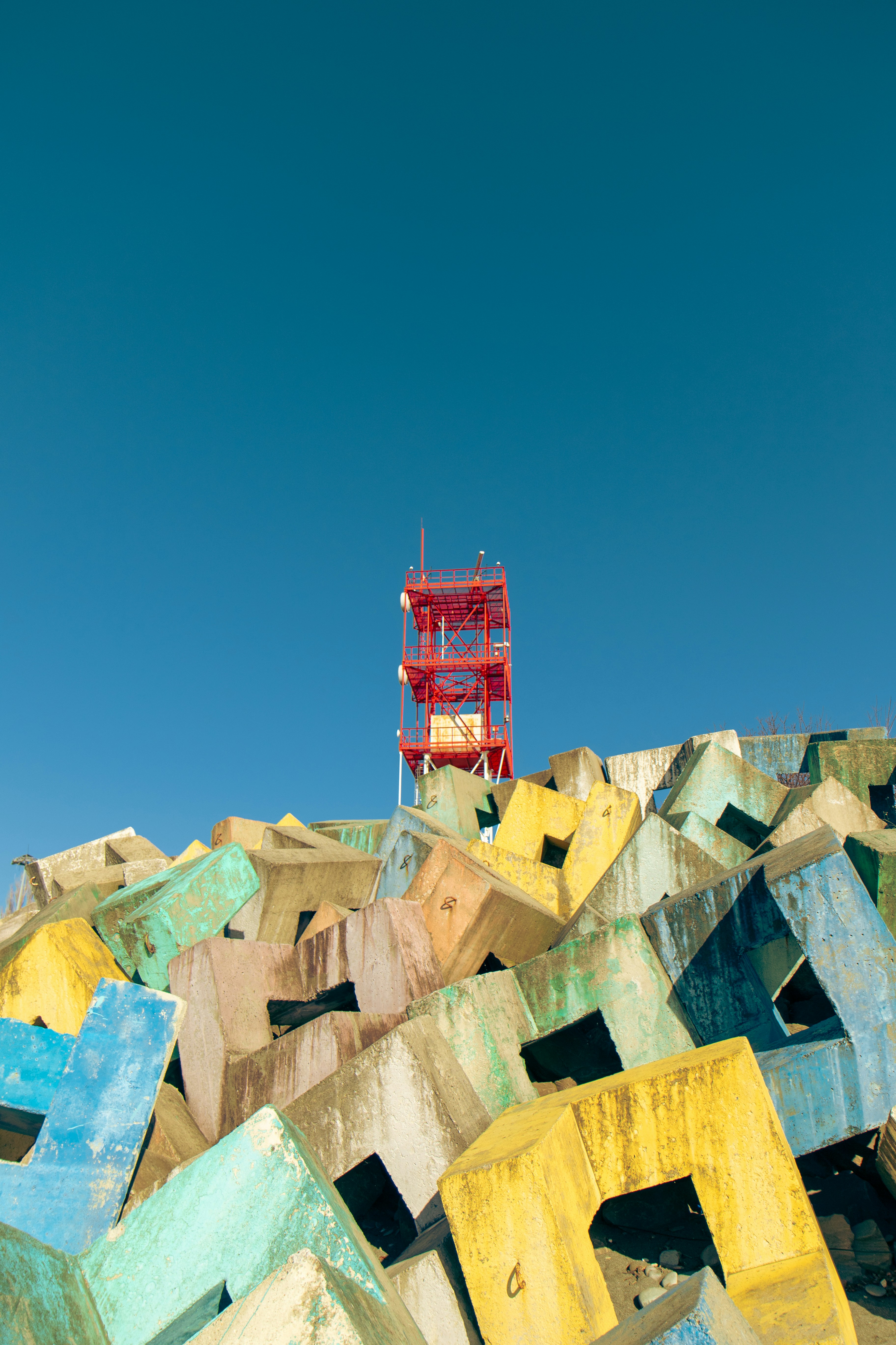 Crimson Watchtower Rising Above a Mosaic of Coastal Tetrapods