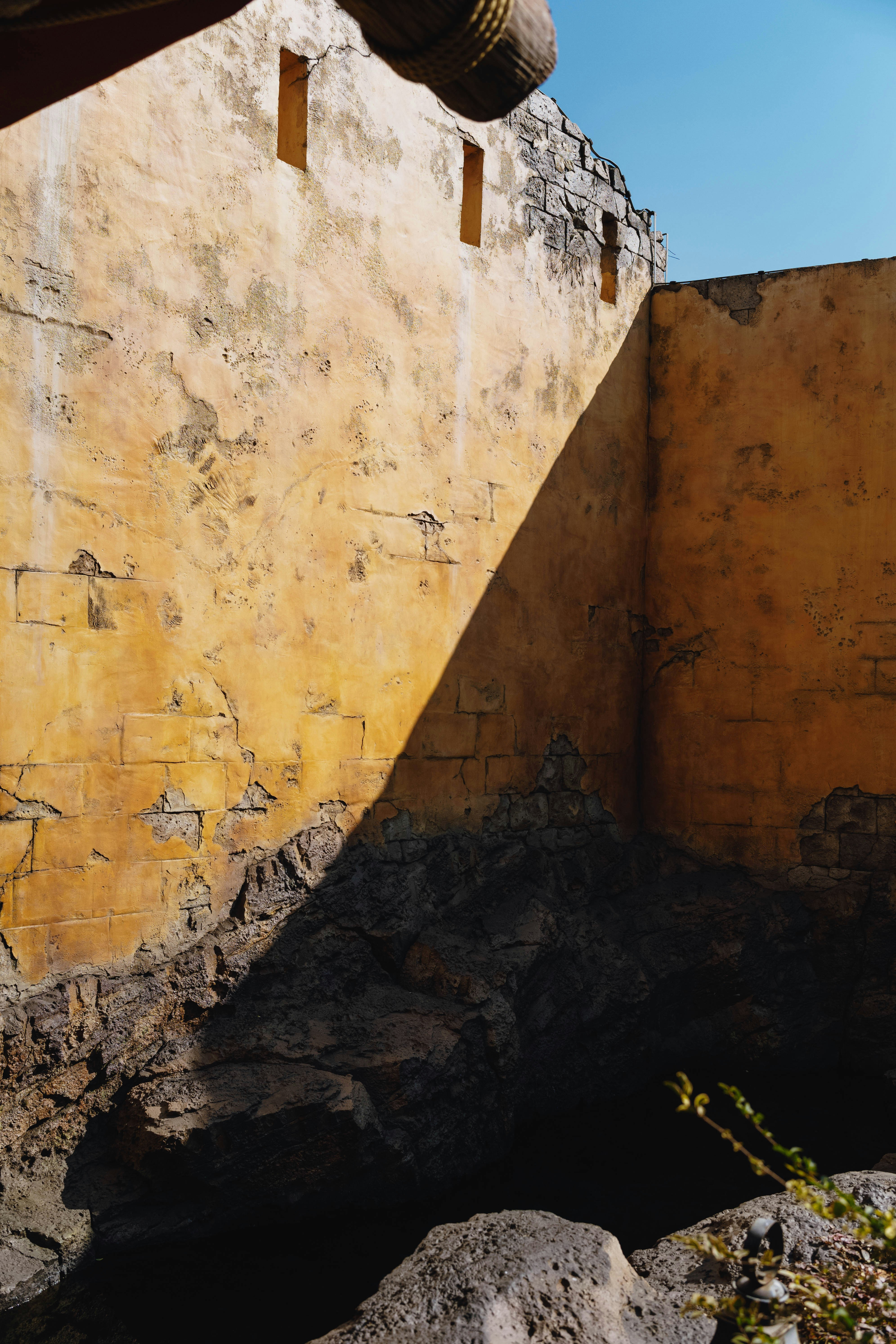 Sunlit Yellow Wall Carved by a Diagonal Shadow in a Coastal Ruin