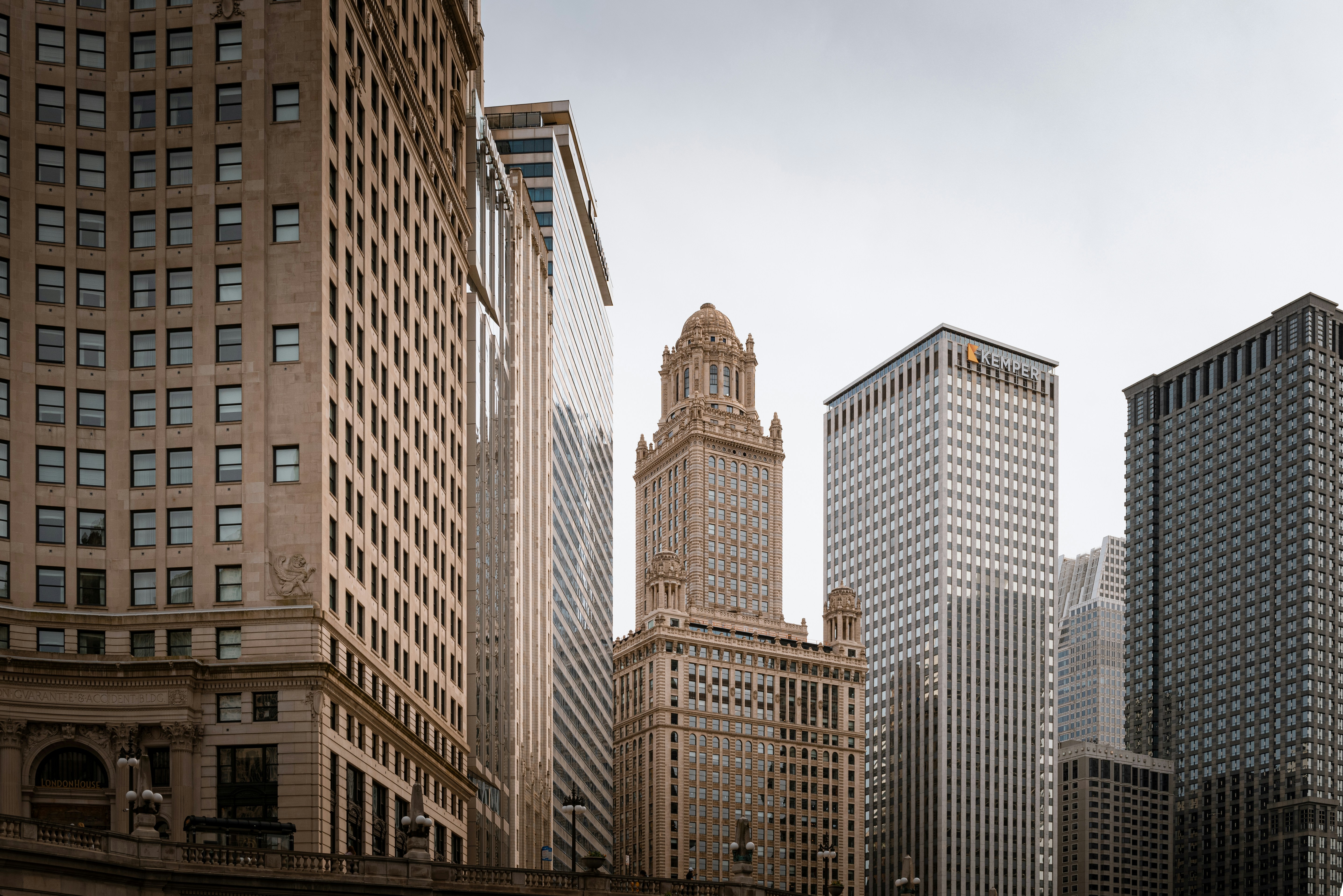 A blend of historic and modern skyscrapers under a muted sky, showcasing architectural contrast and elegance.
