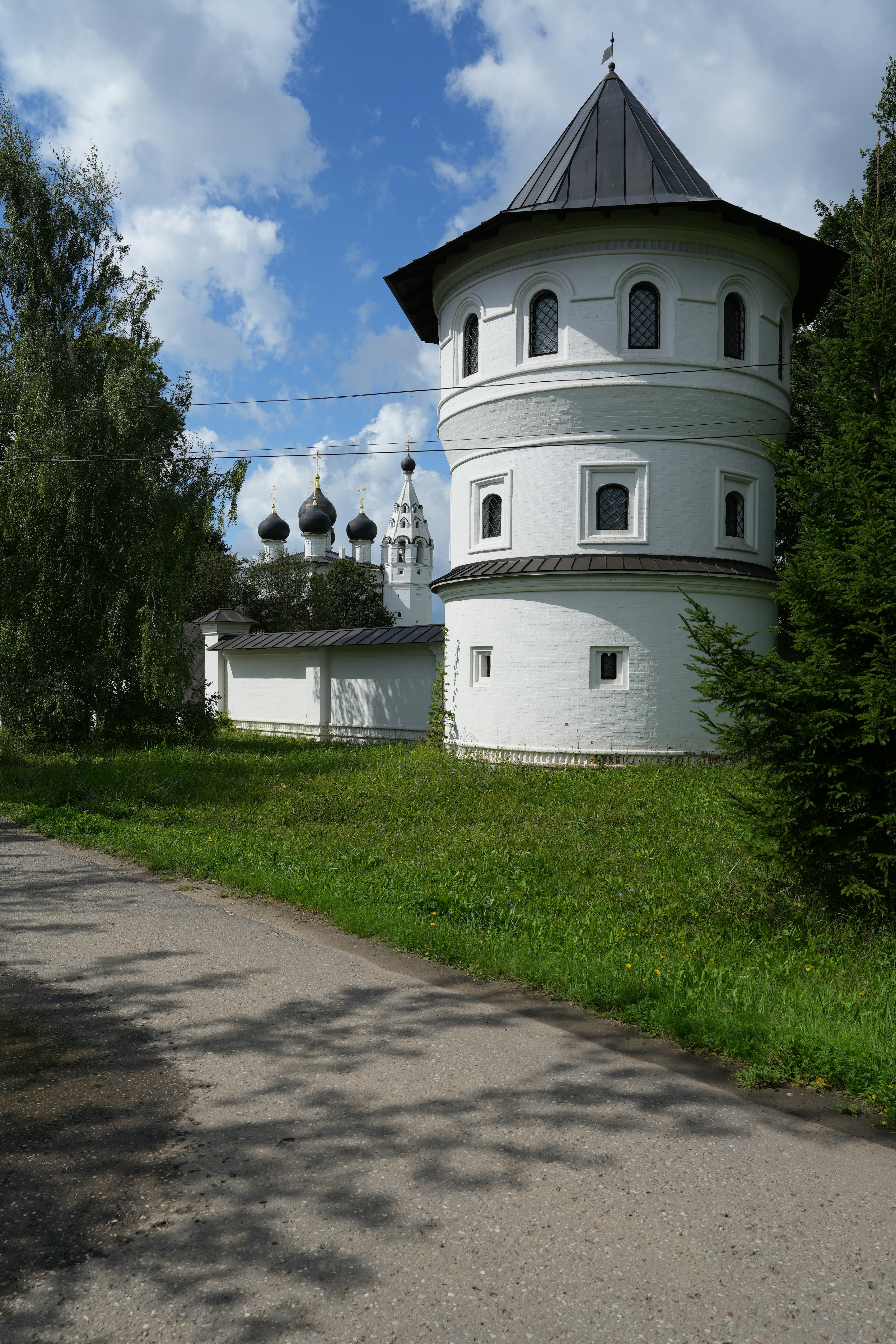 White Cylindrical Tower by the Path: Quiet Architectural Scene with Distant Onion Domes