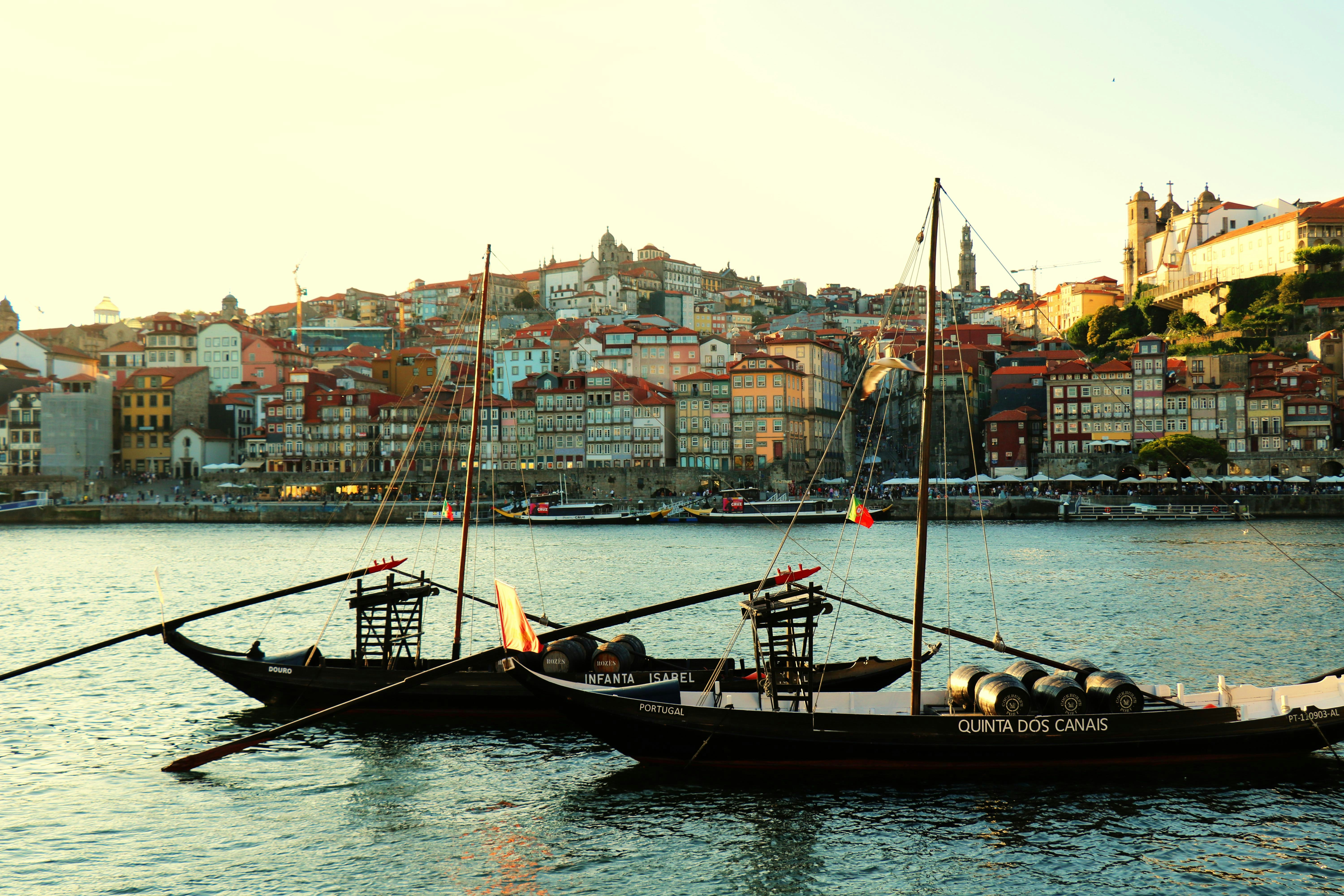 Traditional boats on the Douro River with a hillside cityscape in warm evening light.