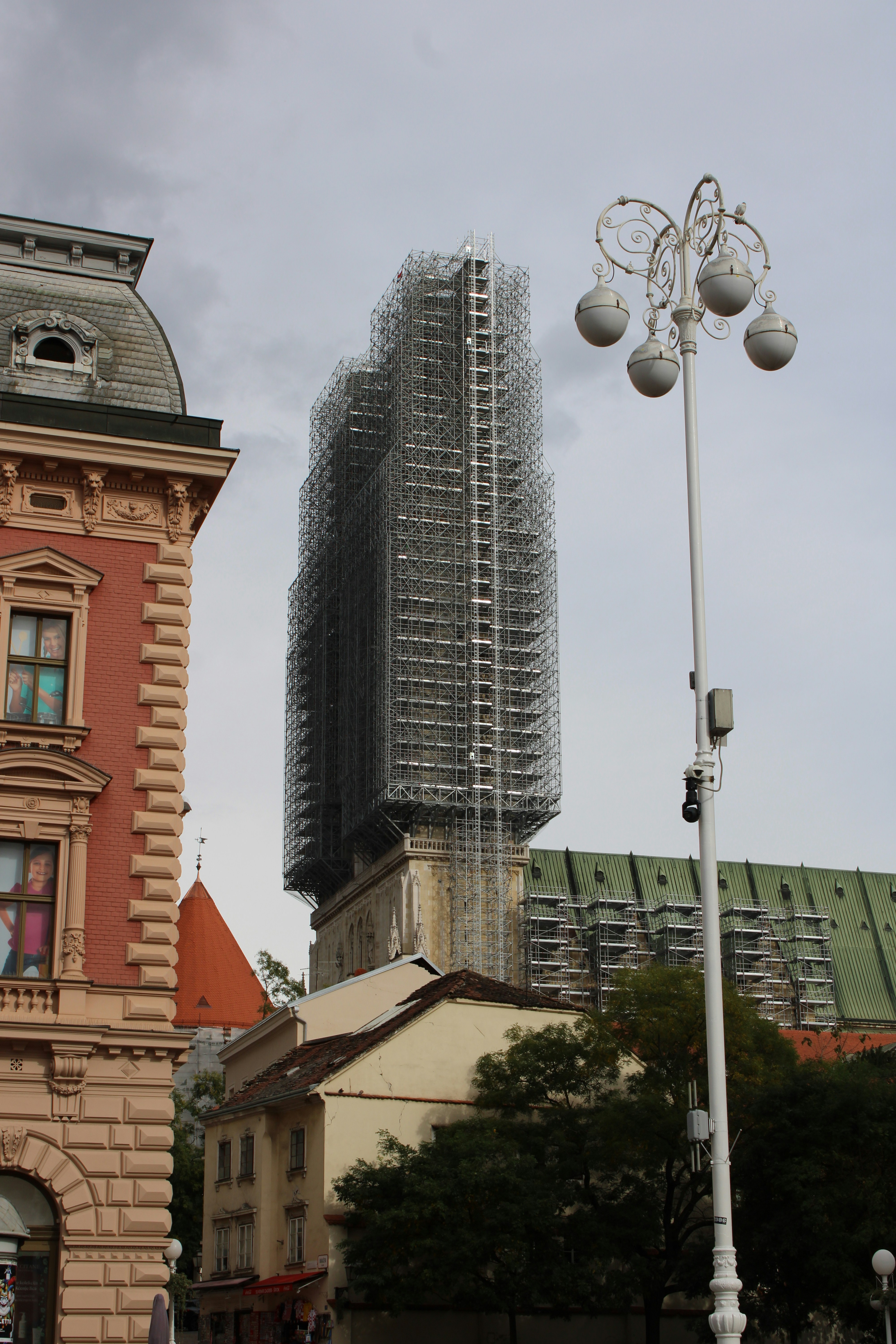 Between Facades: A Scaffolded Tower Rises Over a Historic City Street