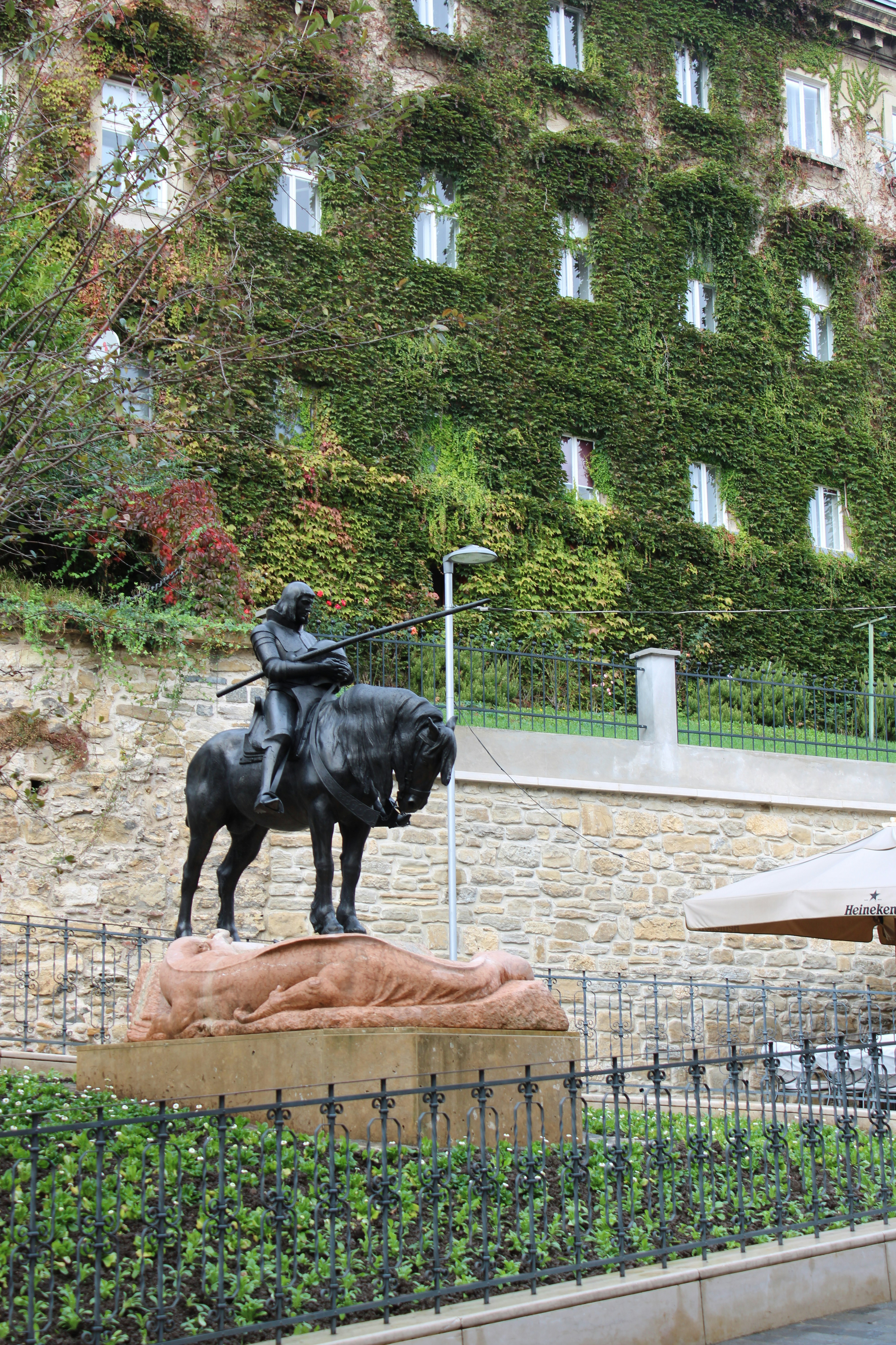 Bronze Rider on a Prancing Horse Beneath an Ivy-Wrapped Wall