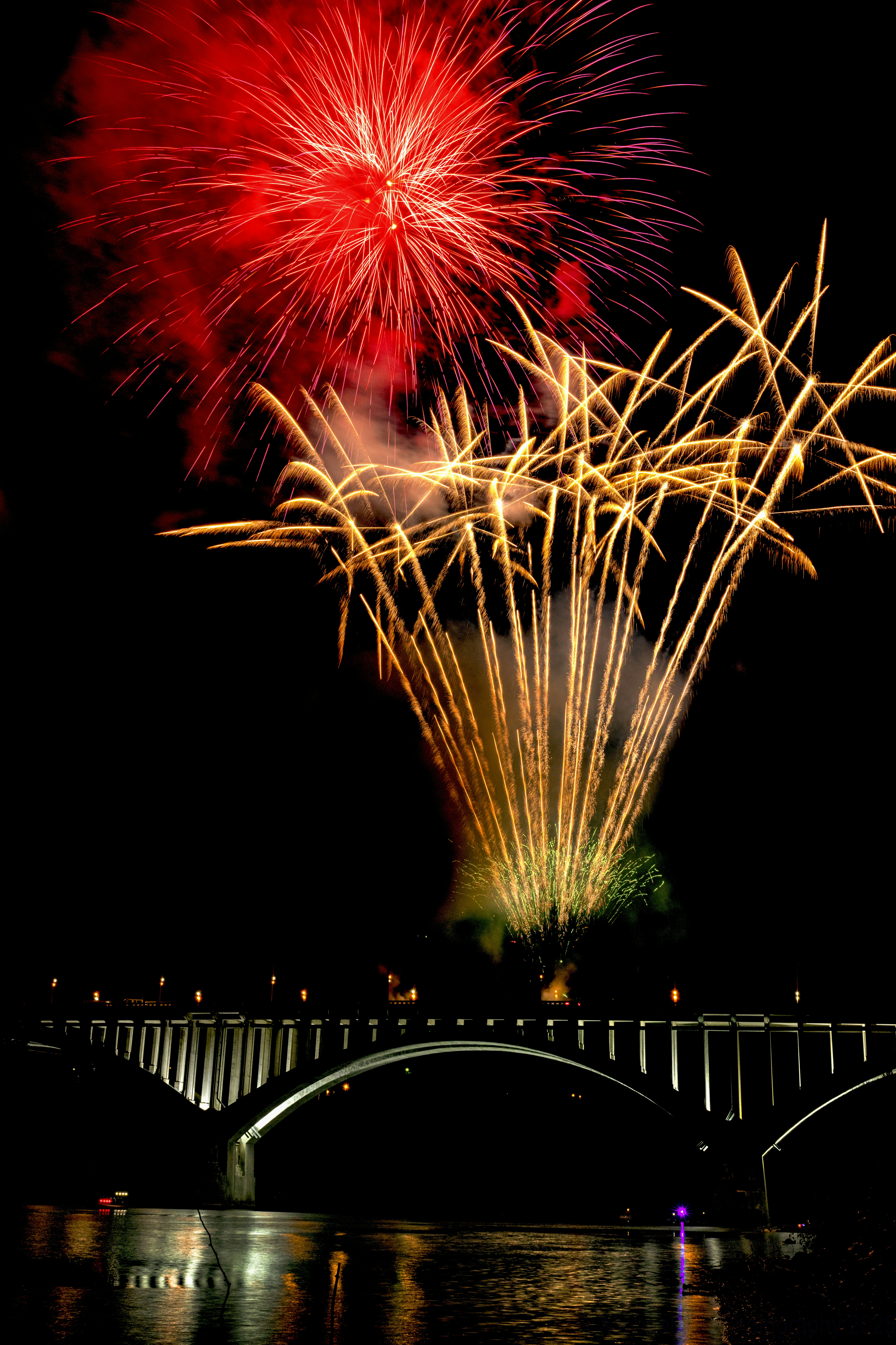Fireworks are lit up in the night sky over a bridge photo – Free ...