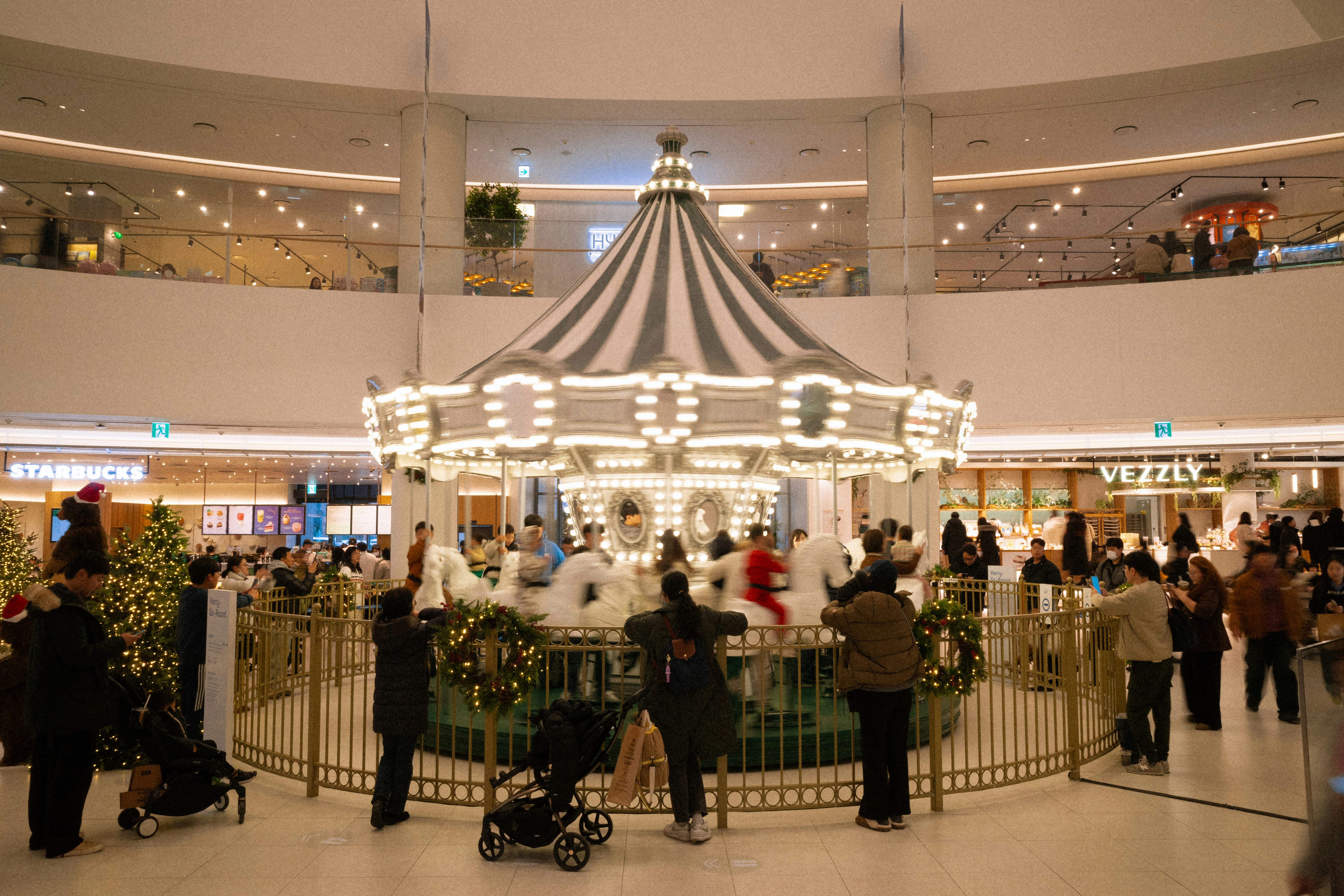 A carousel inside of a building with people standing around photo ...
