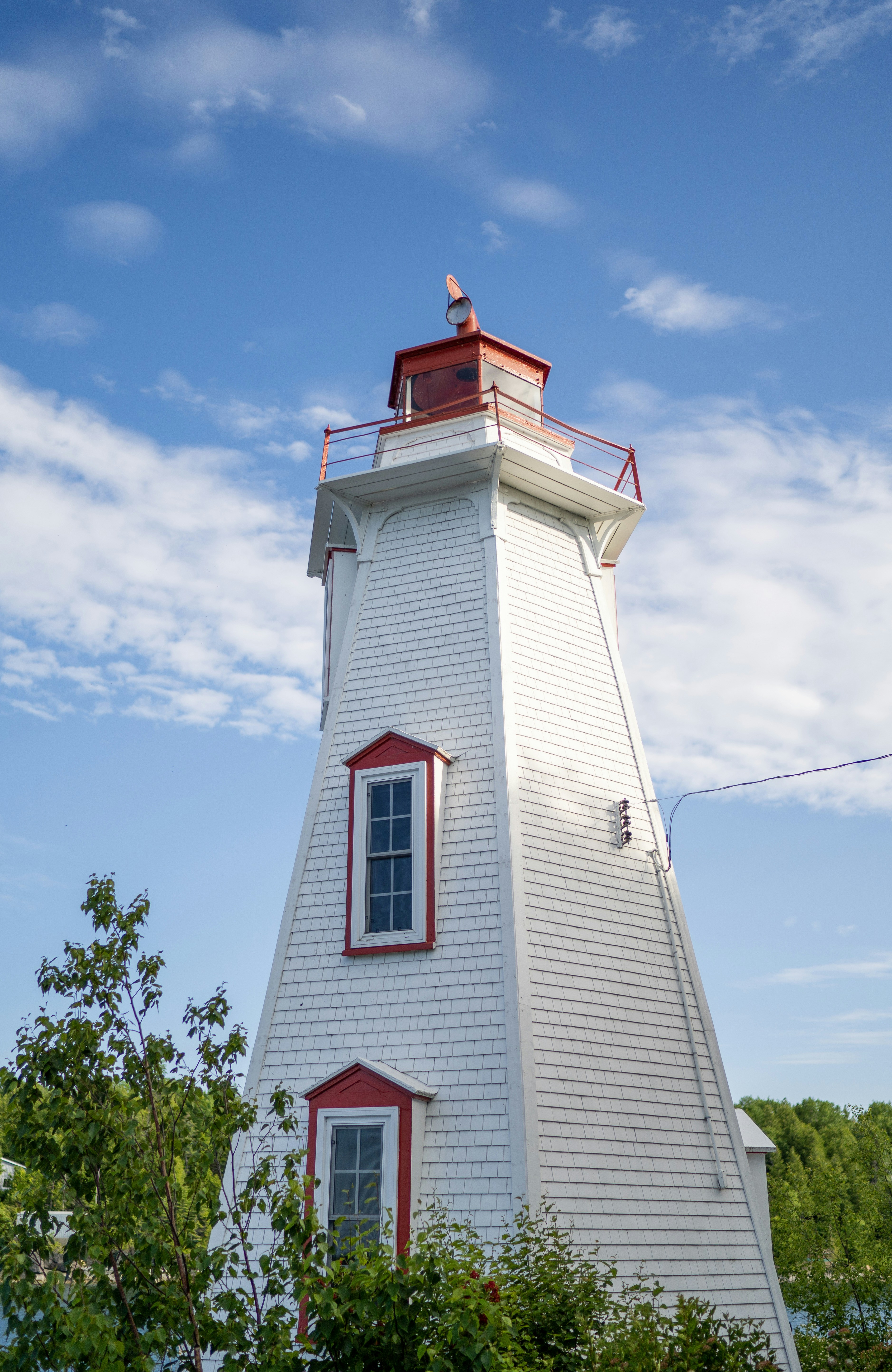 Crimson-Trimmed Lighthouse Reaching Toward a Vast Blue Sky