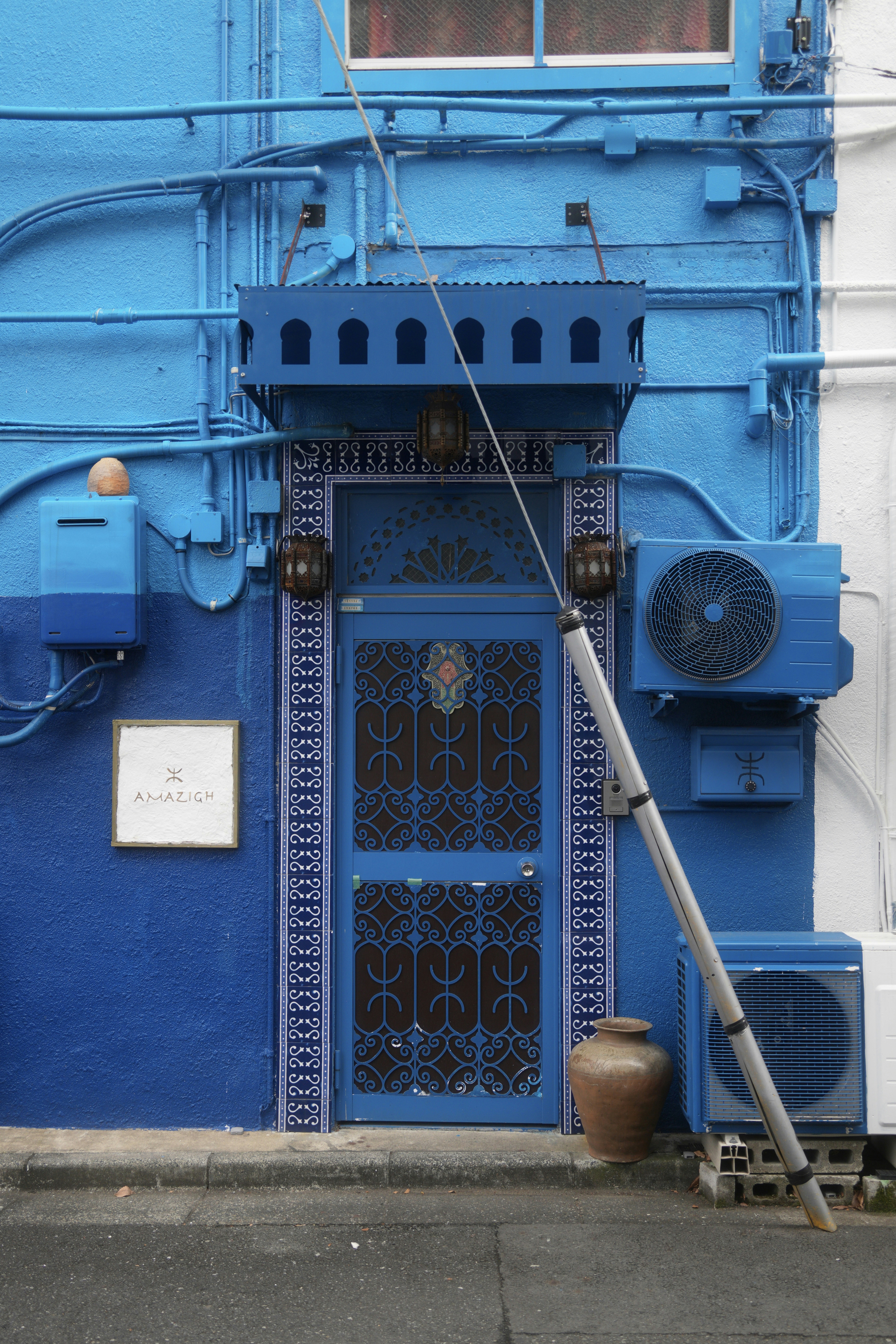 Cerulean Portal: Ornate Gate Beneath a Web of Urban Piping