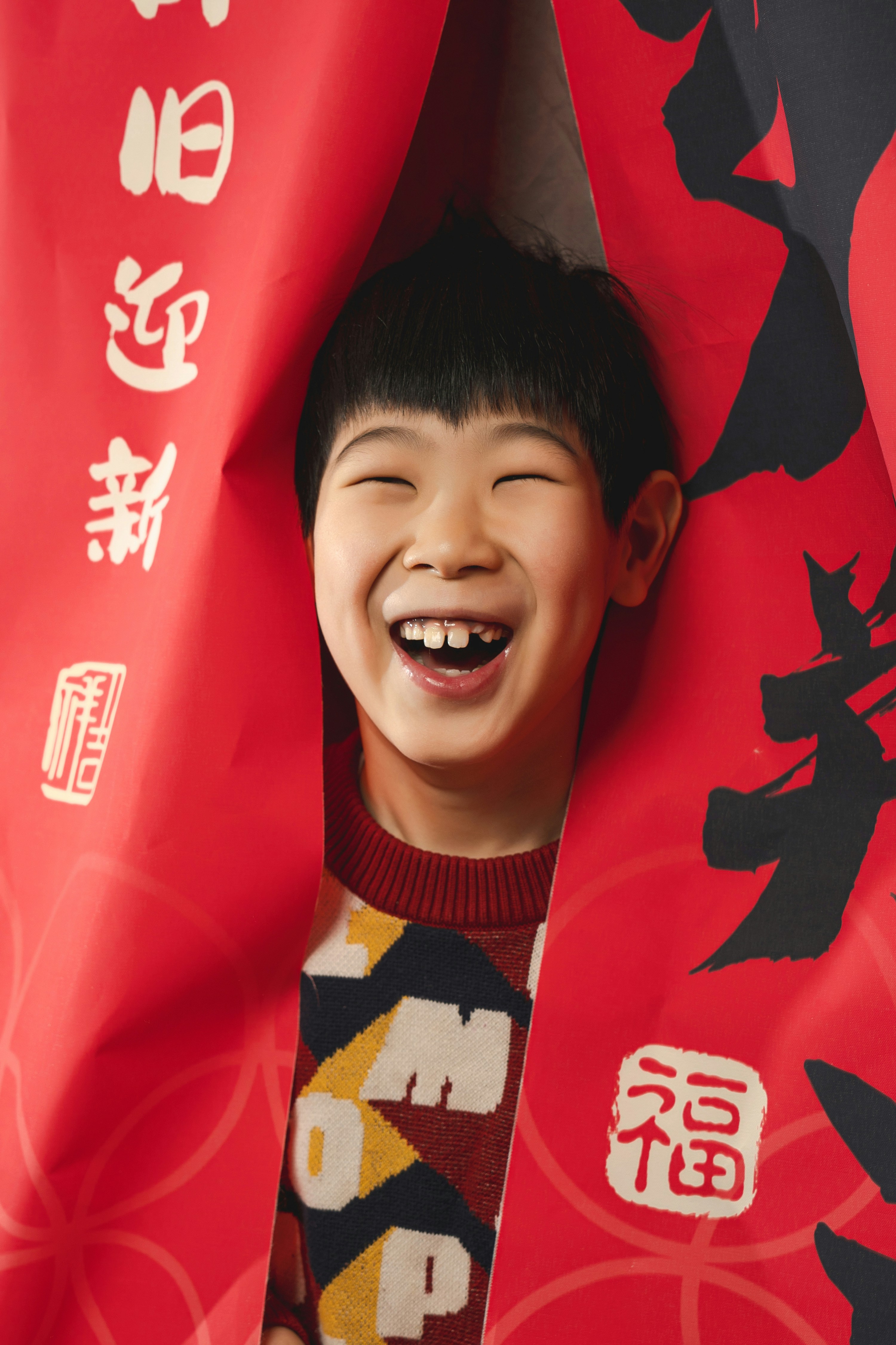 A young boy is smiling and hiding behind a red banner photo – Free ...