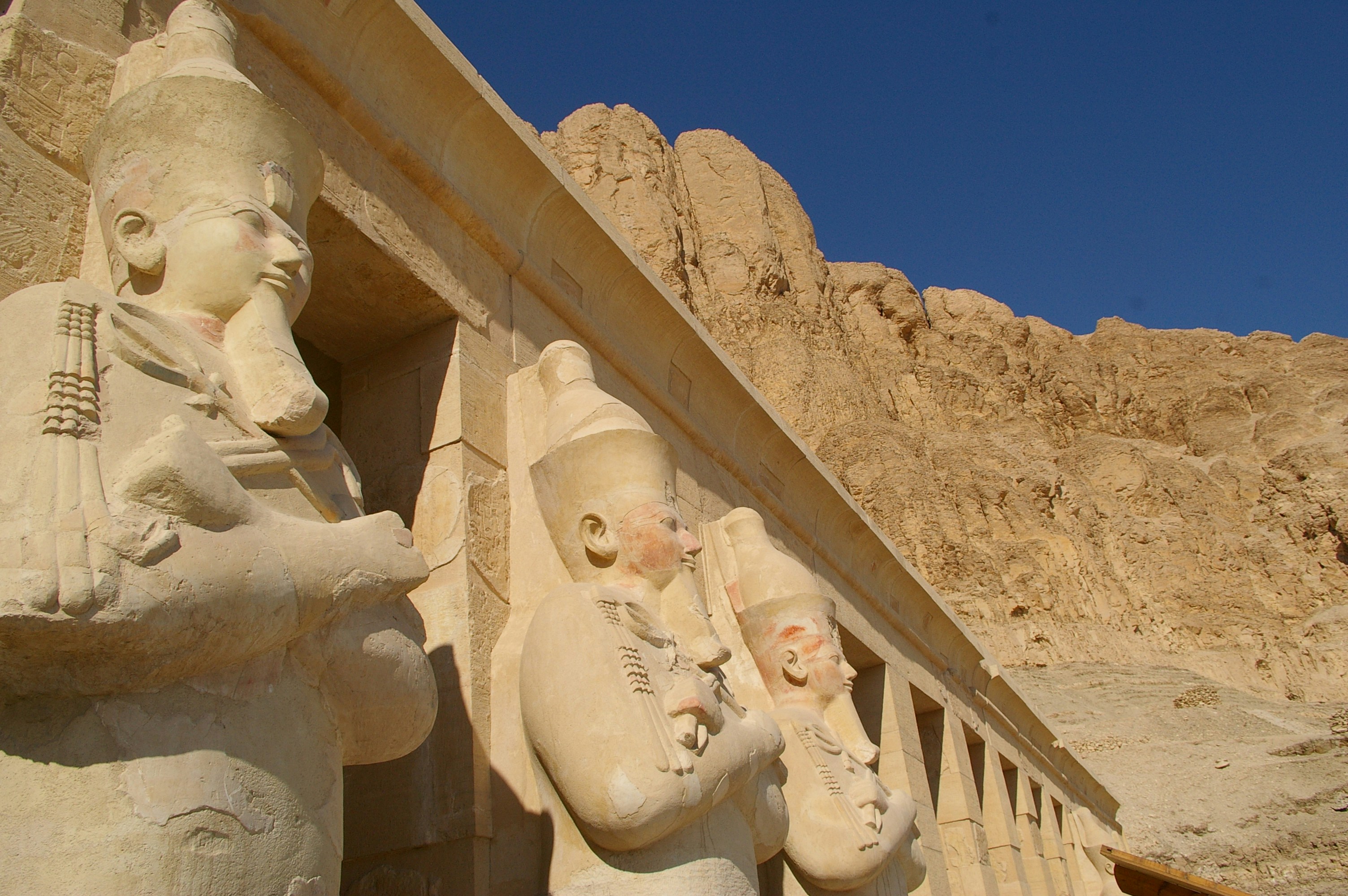 Three intricately carved statues stand against a backdrop of rocky cliffs, showcasing the artistry of ancient civilization.