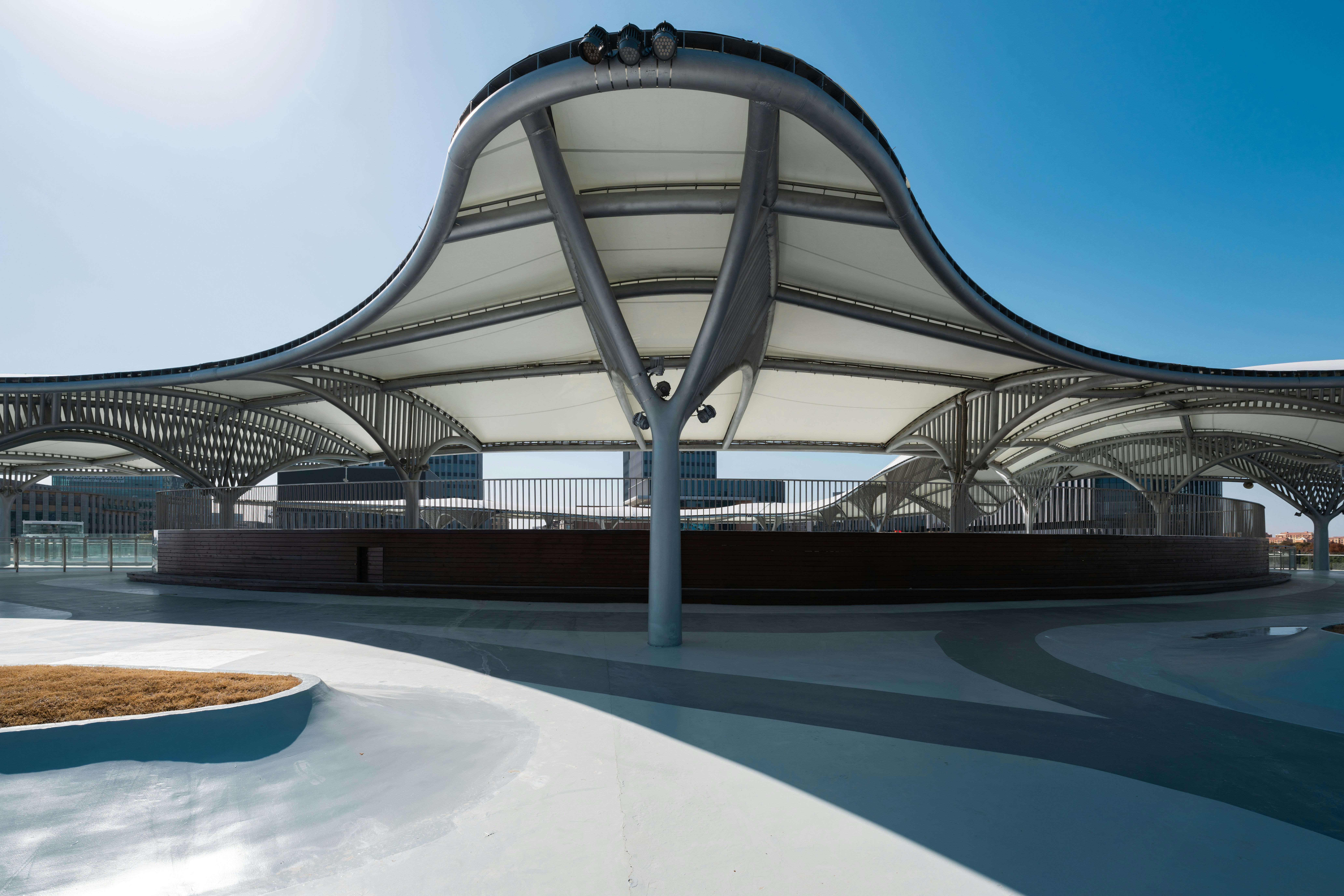 Architectural canopy with sleek metal lines and geometric structures against a clear blue sky.