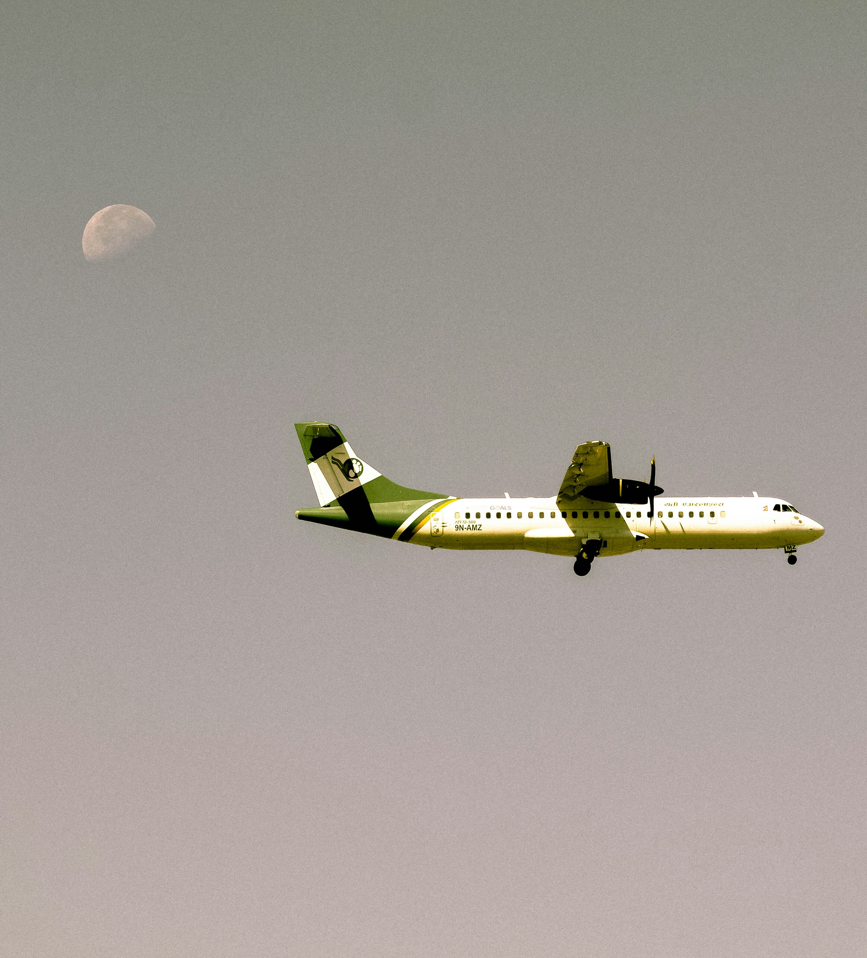 A plane flying in the sky with a half moon in the background photo ...