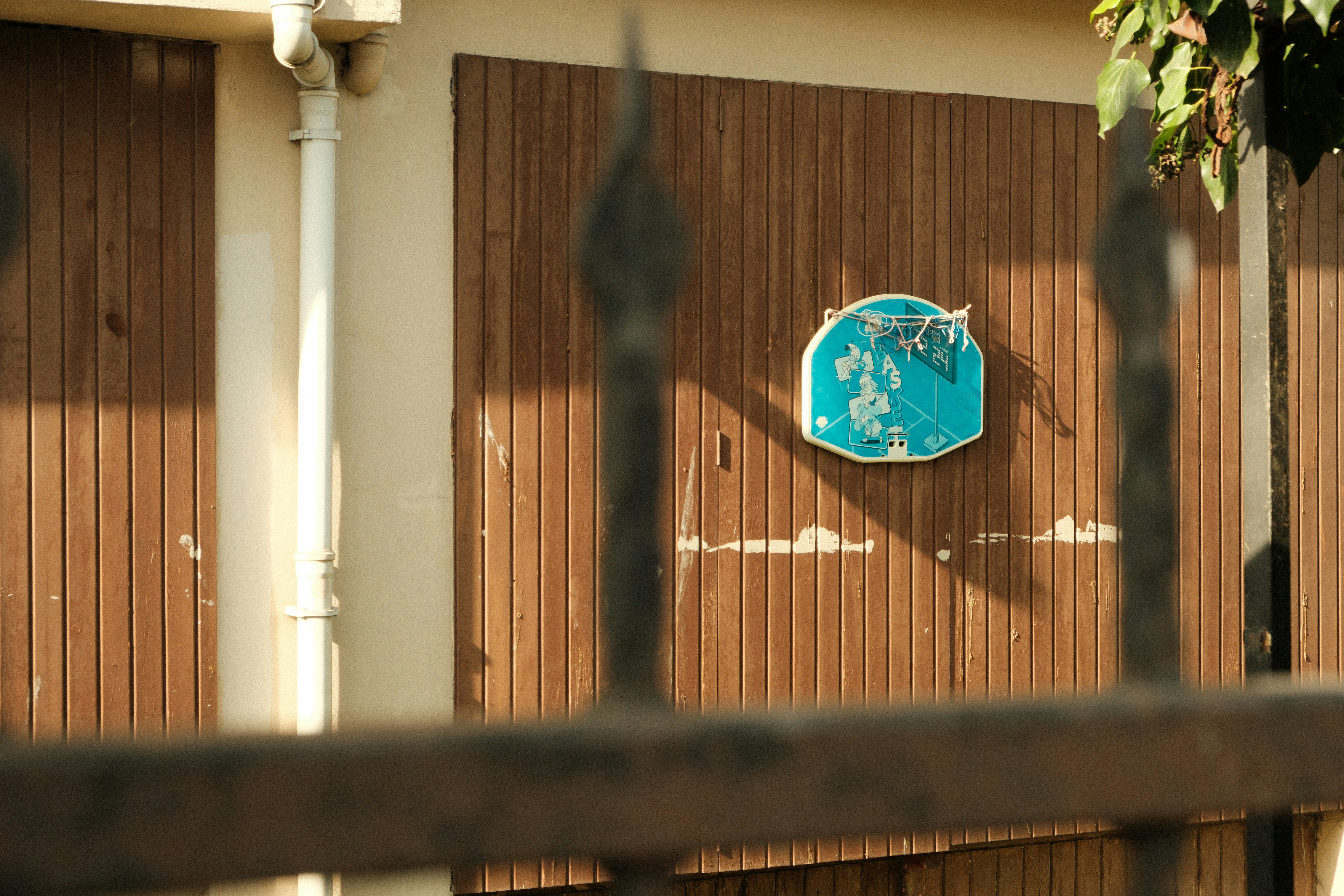 Cerulean Emblem on a Sunlit Wooden Door Framed by Iron Bars