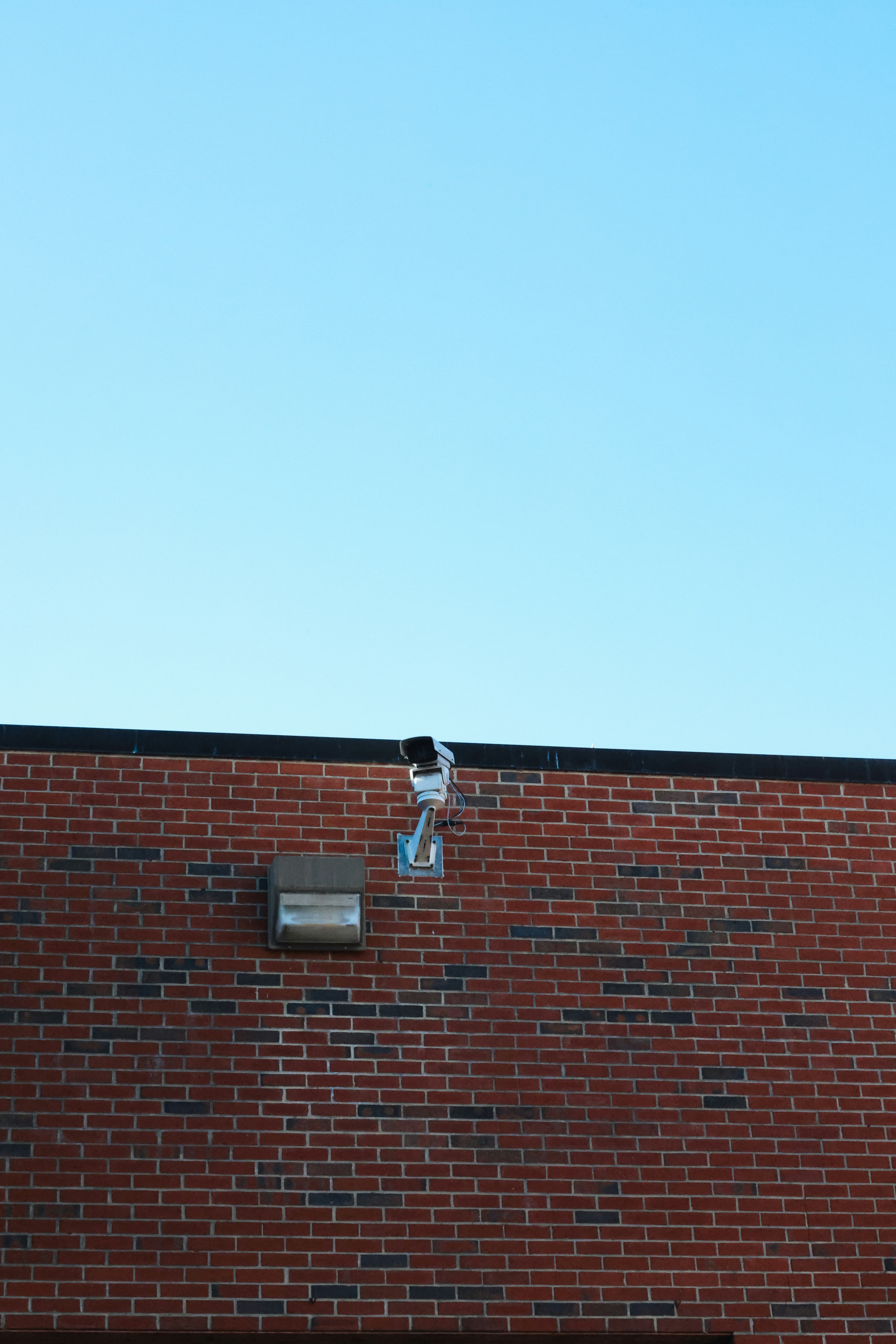 Security Camera Over Brick Wall Beneath an Open Sky
