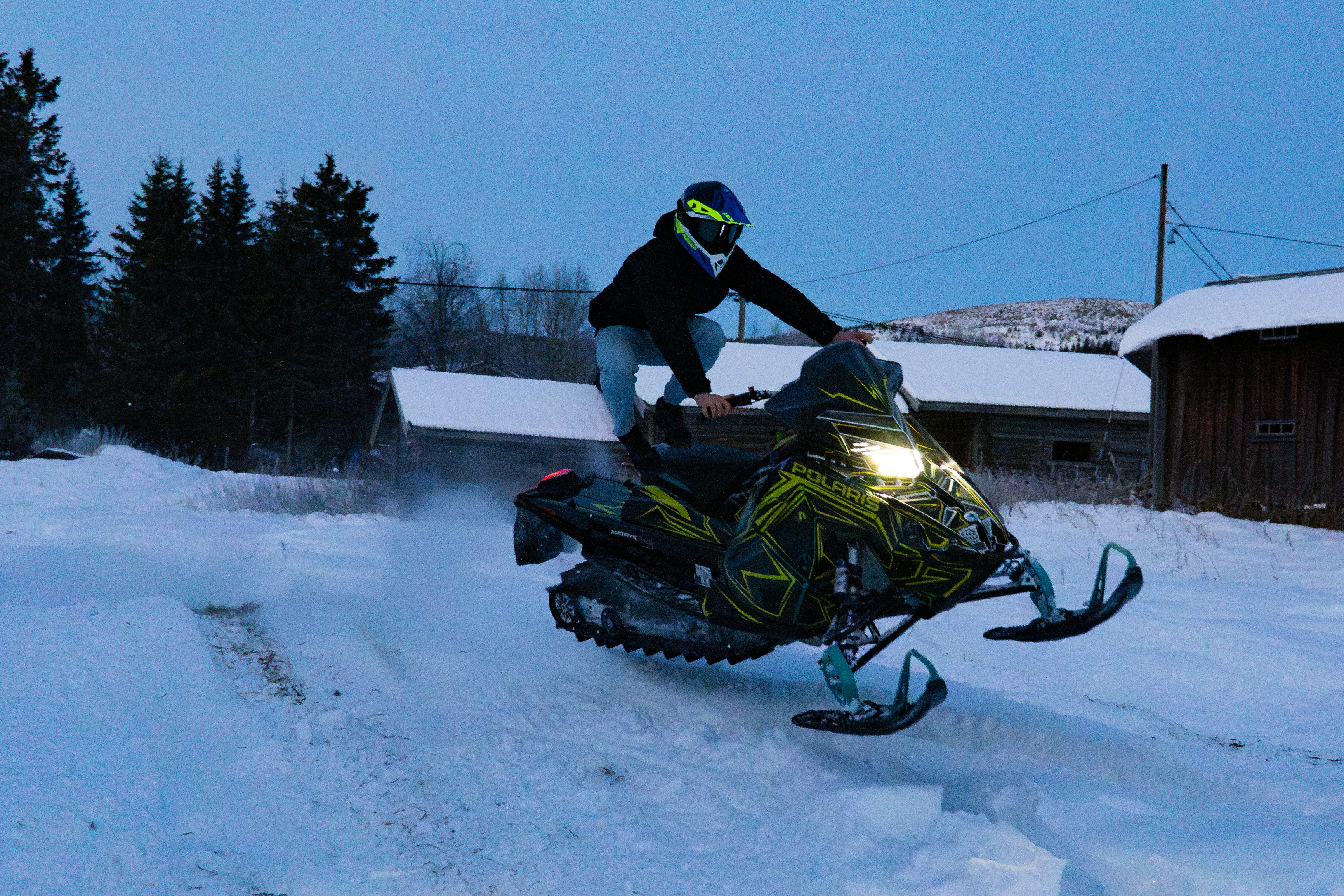 Neon-Tuned Jump: Snowmobile Soars Over a Snow-Covered Backroad at Blue Hour