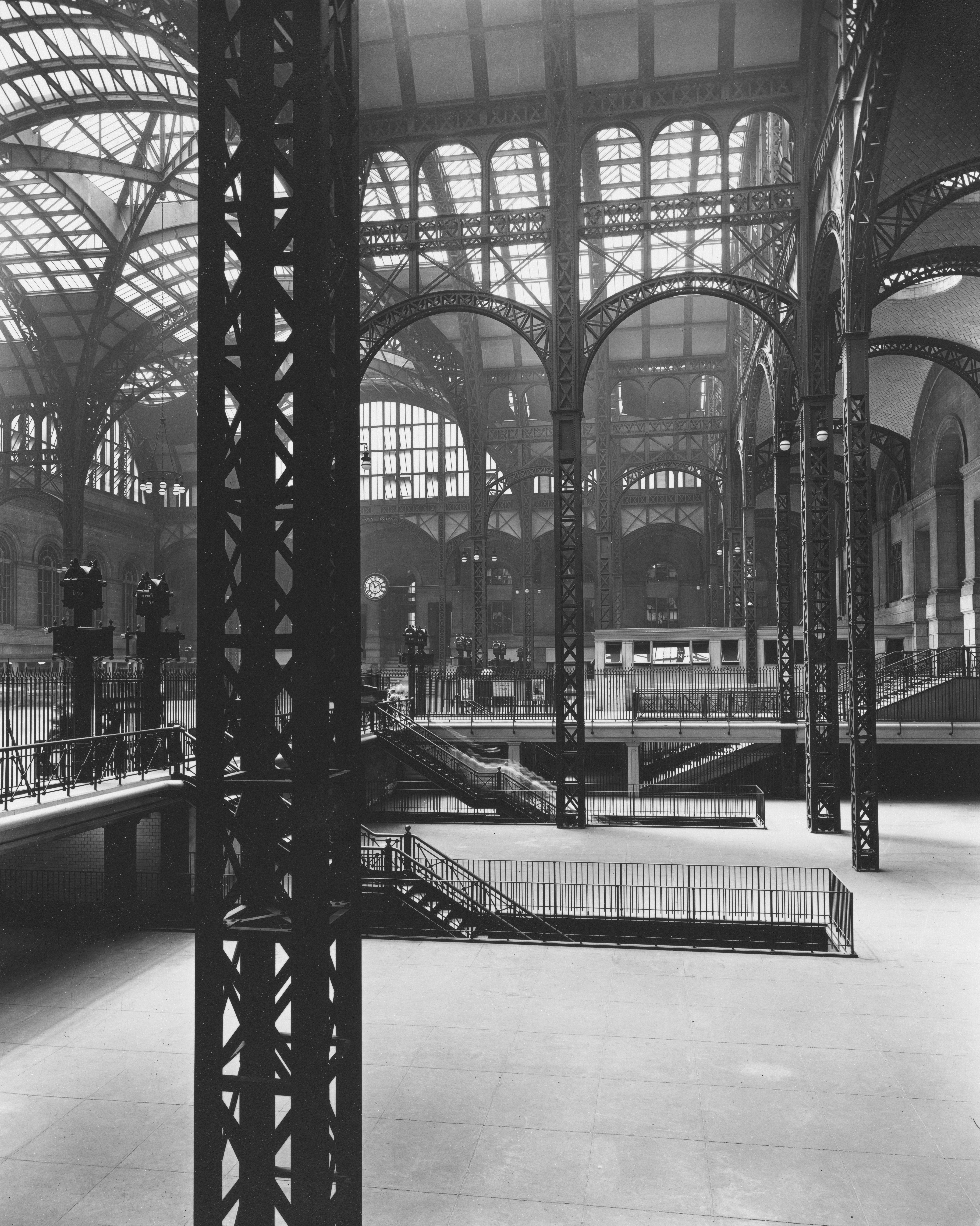 Grand arches and ironwork of historic Penn Station with diffused natural light highlighting architectural details.