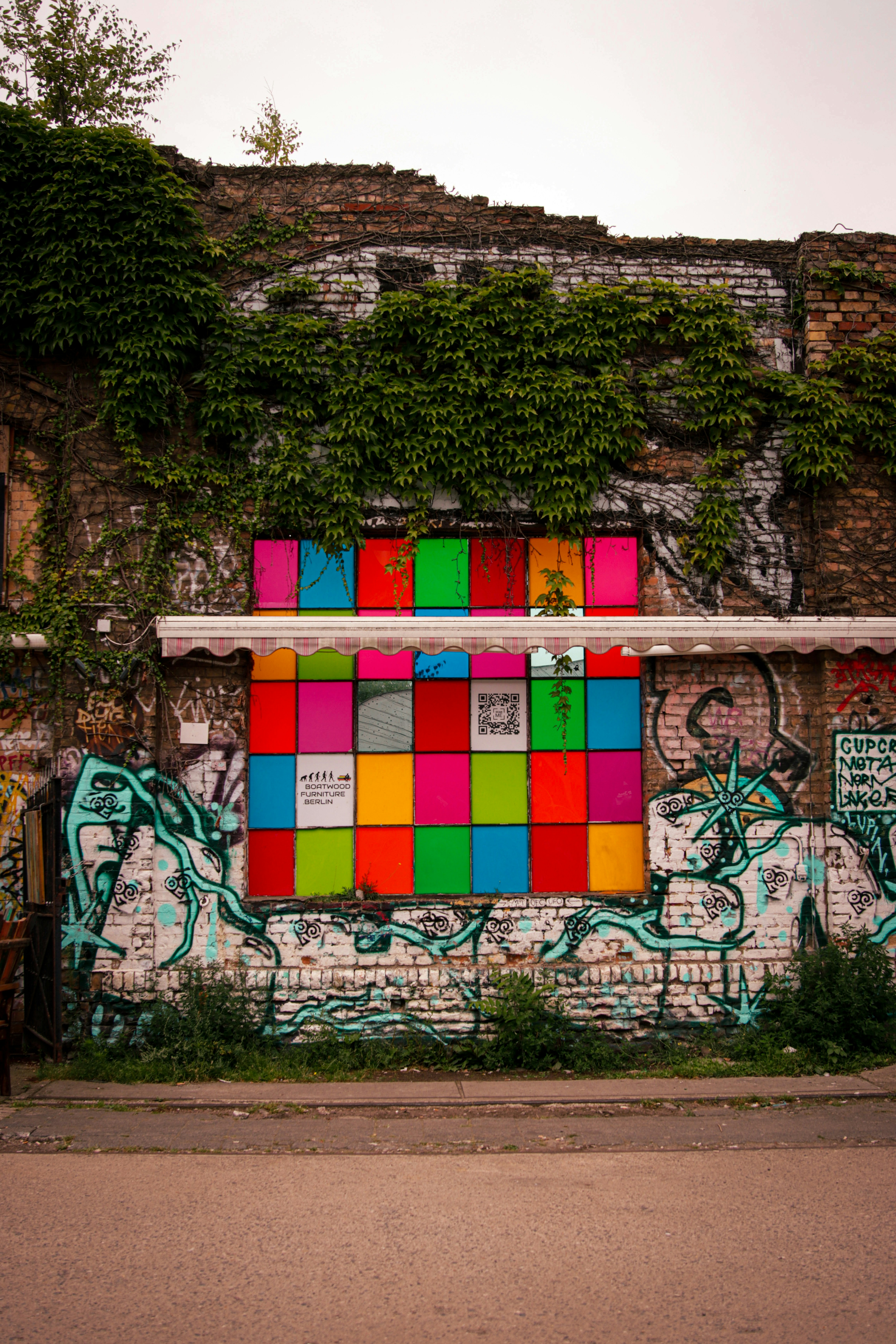 Color Mosaic on a Graffitied Wall Under Ivy Clad Ruins