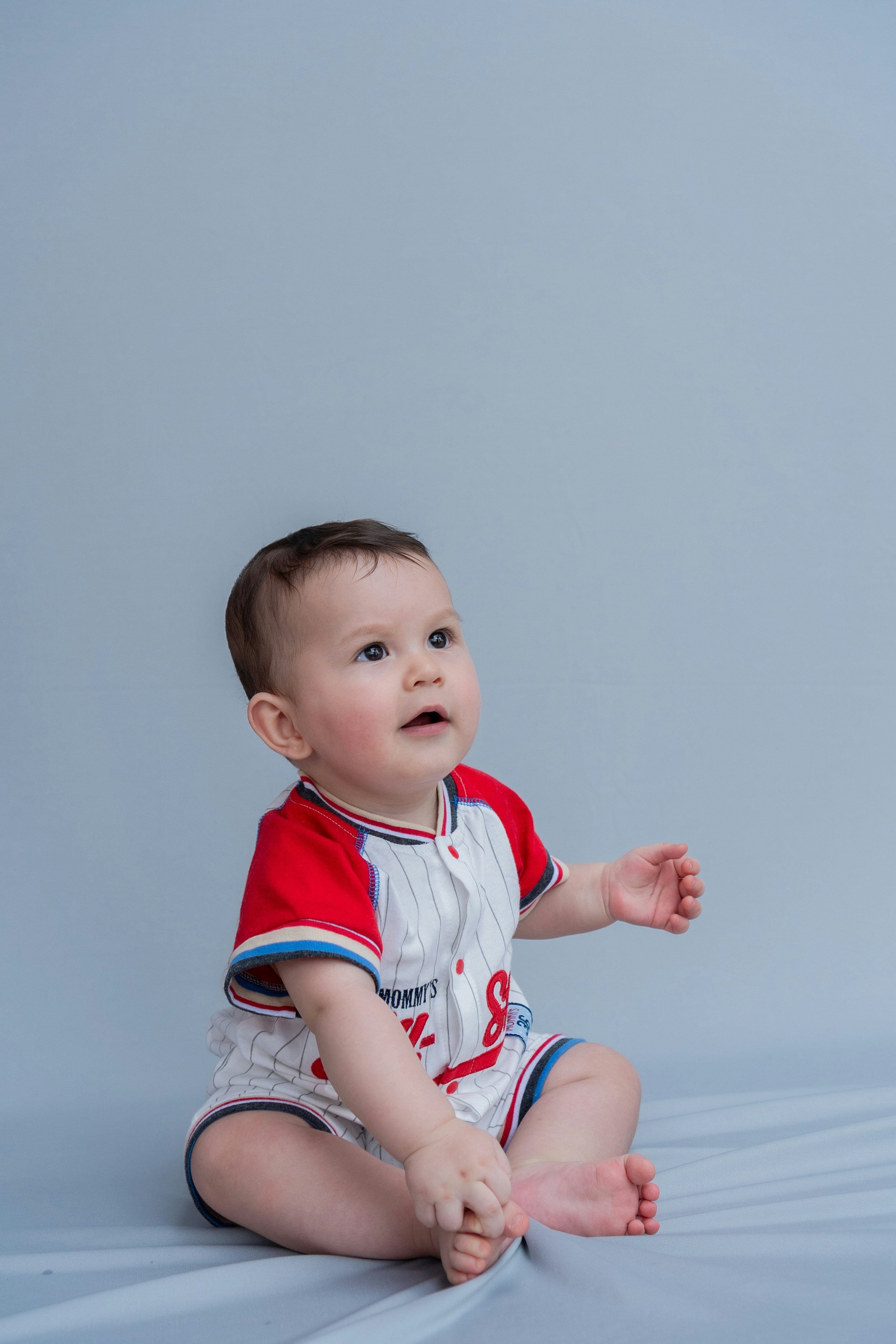 Soft Light, Big Smile: A Baby’s Curious Gaze Against a Mint Screen
