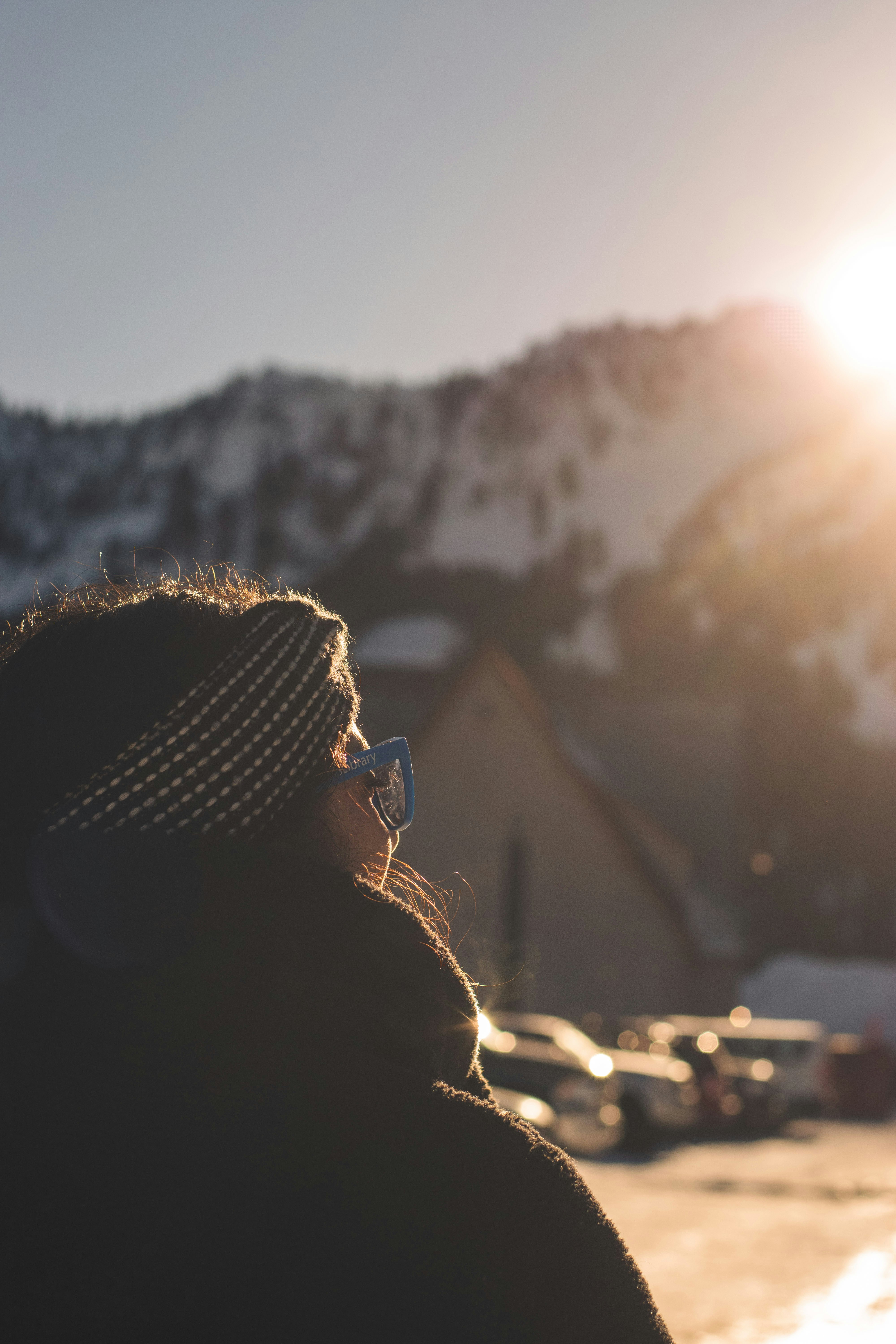 Silhouetted person gazing at the sunlit snowy mountains with a clear sky.