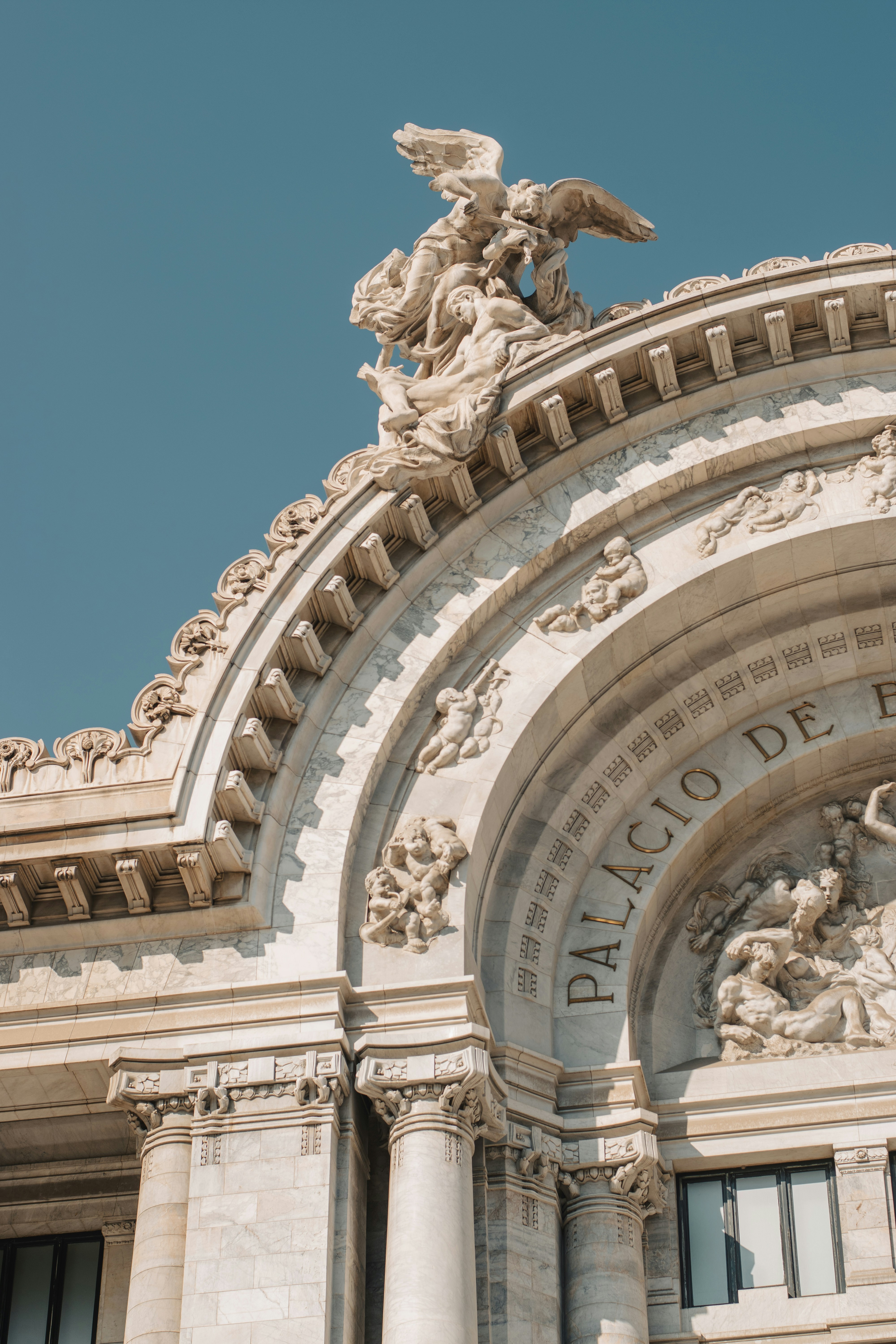 Ornate stone facade of an historic building with sculptural details under a clear blue sky.