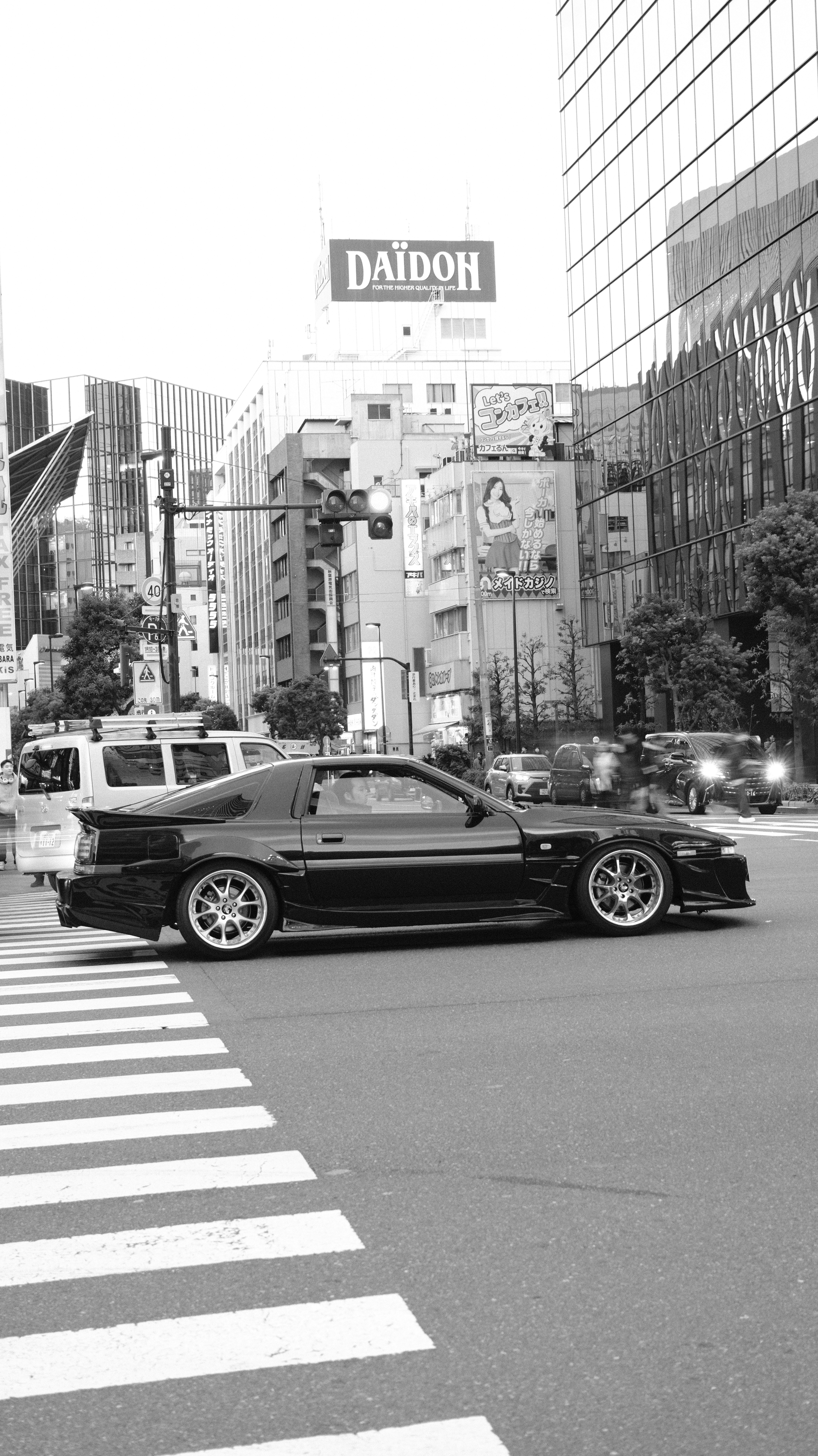 Low-slung Black Coupe at a City Intersection: A Quiet Moment Amid Glass and Signage