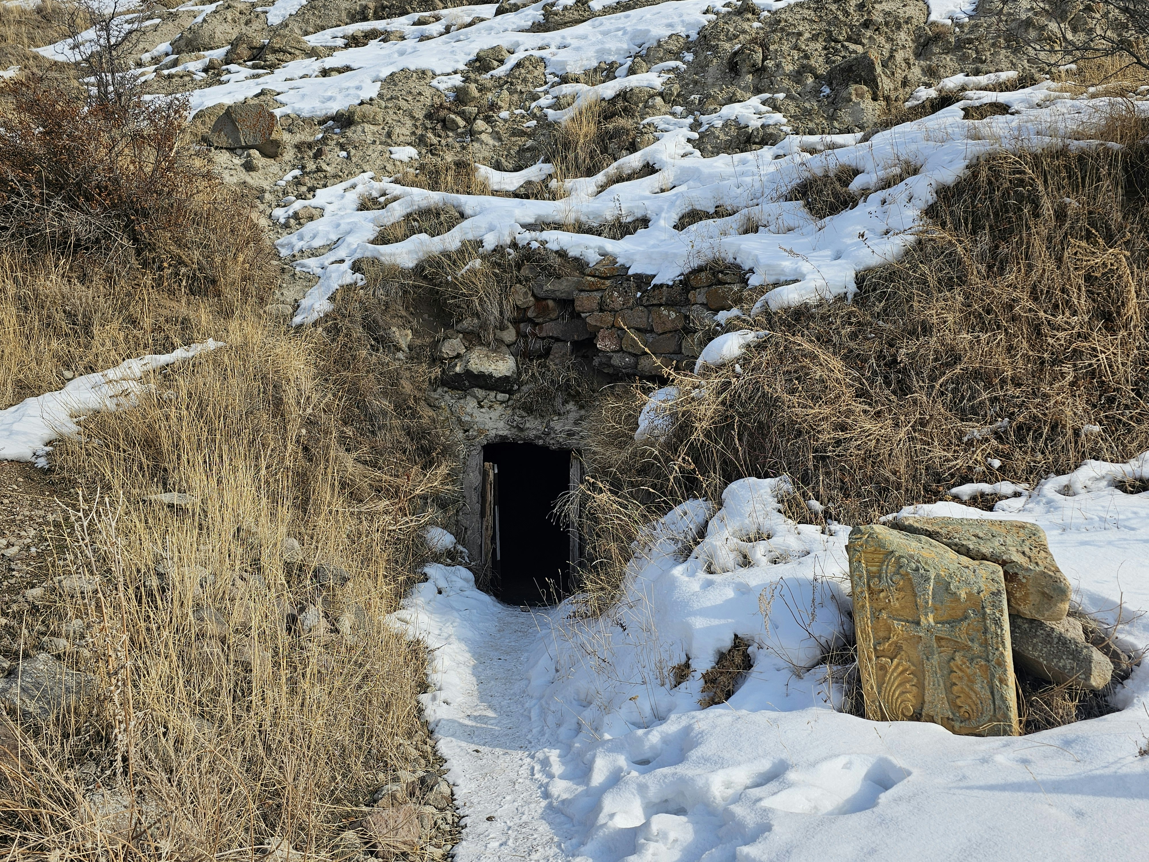 Snow-Dusted Passage: A Hidden Tunnel in a Weathered Stone Wall