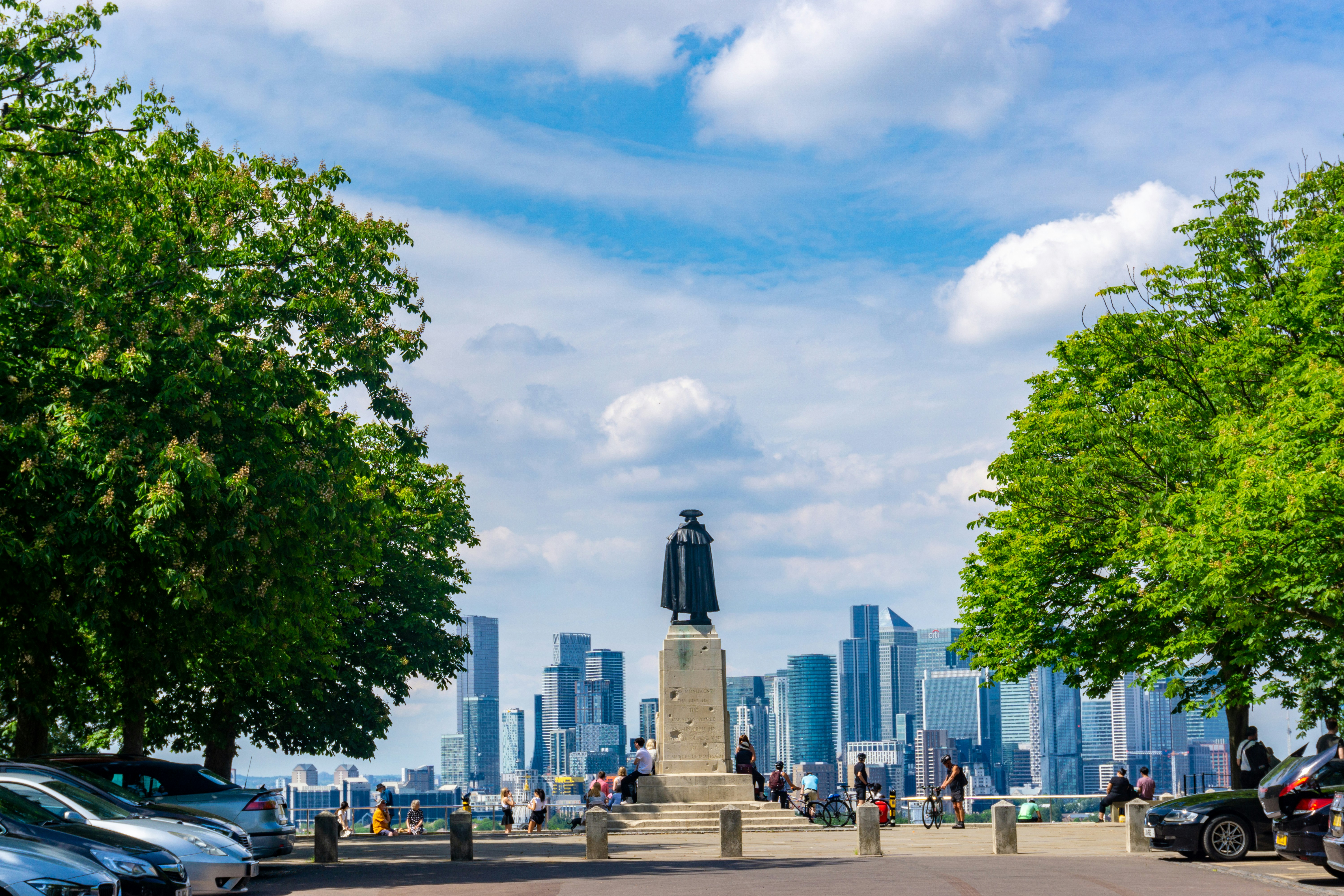 Statue and skyline vantage: a plaza framed by green arching trees