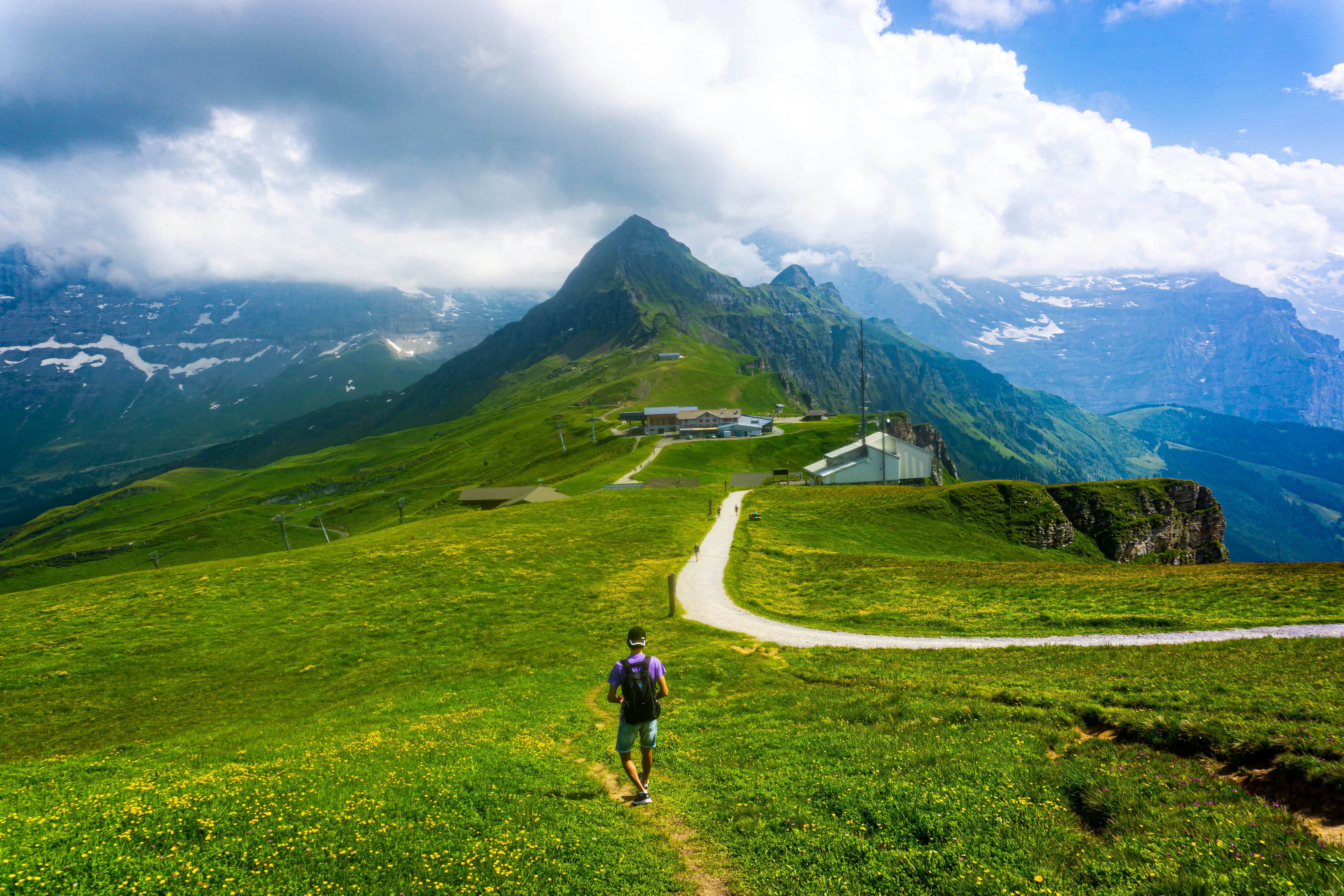 A man hiking up a grassy hill with mountains in the background photo ...