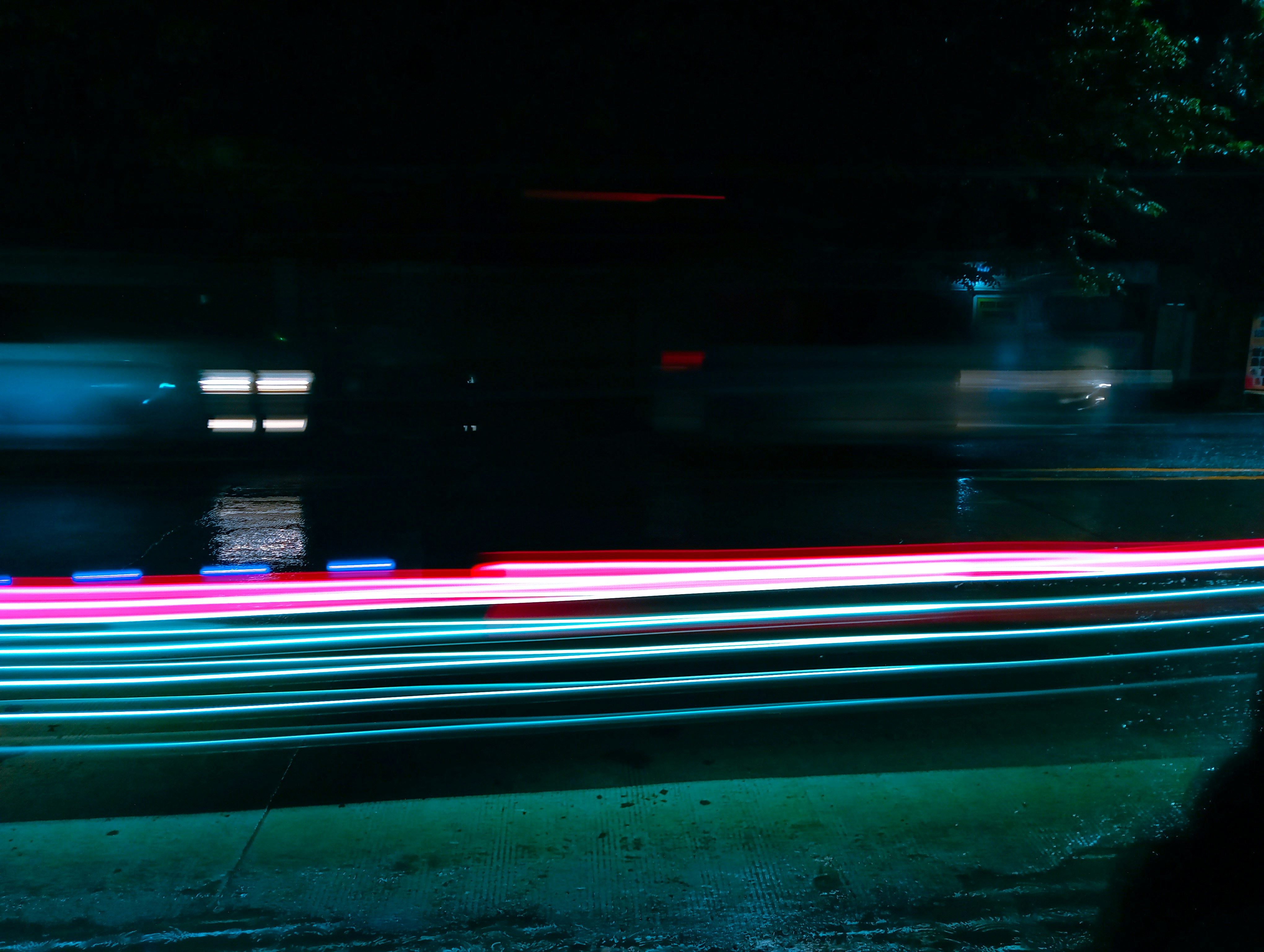 Long exposure of colorful light trails on a wet street at night.