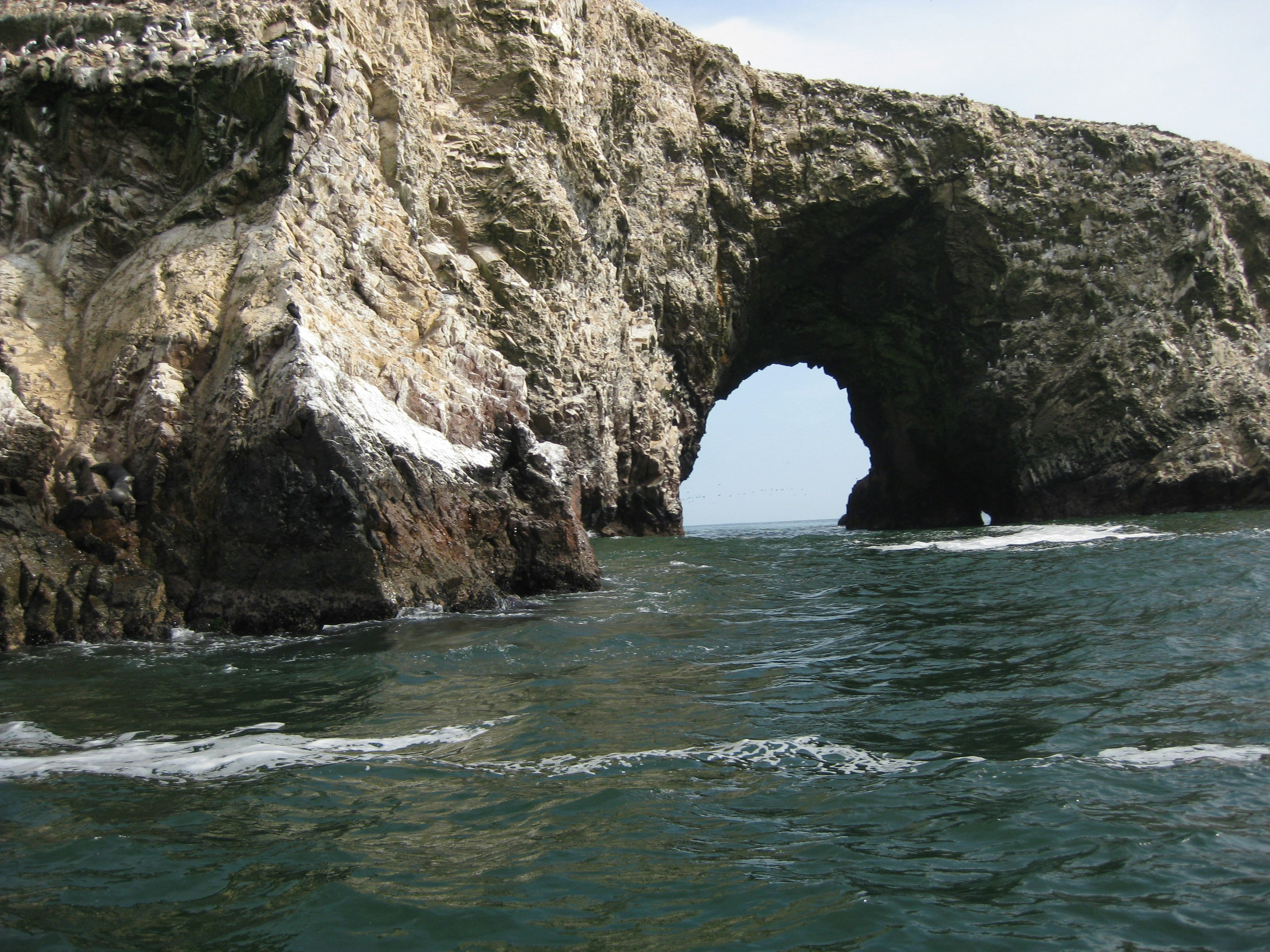 A large rock formation in the middle of a body of water photo – Free ...