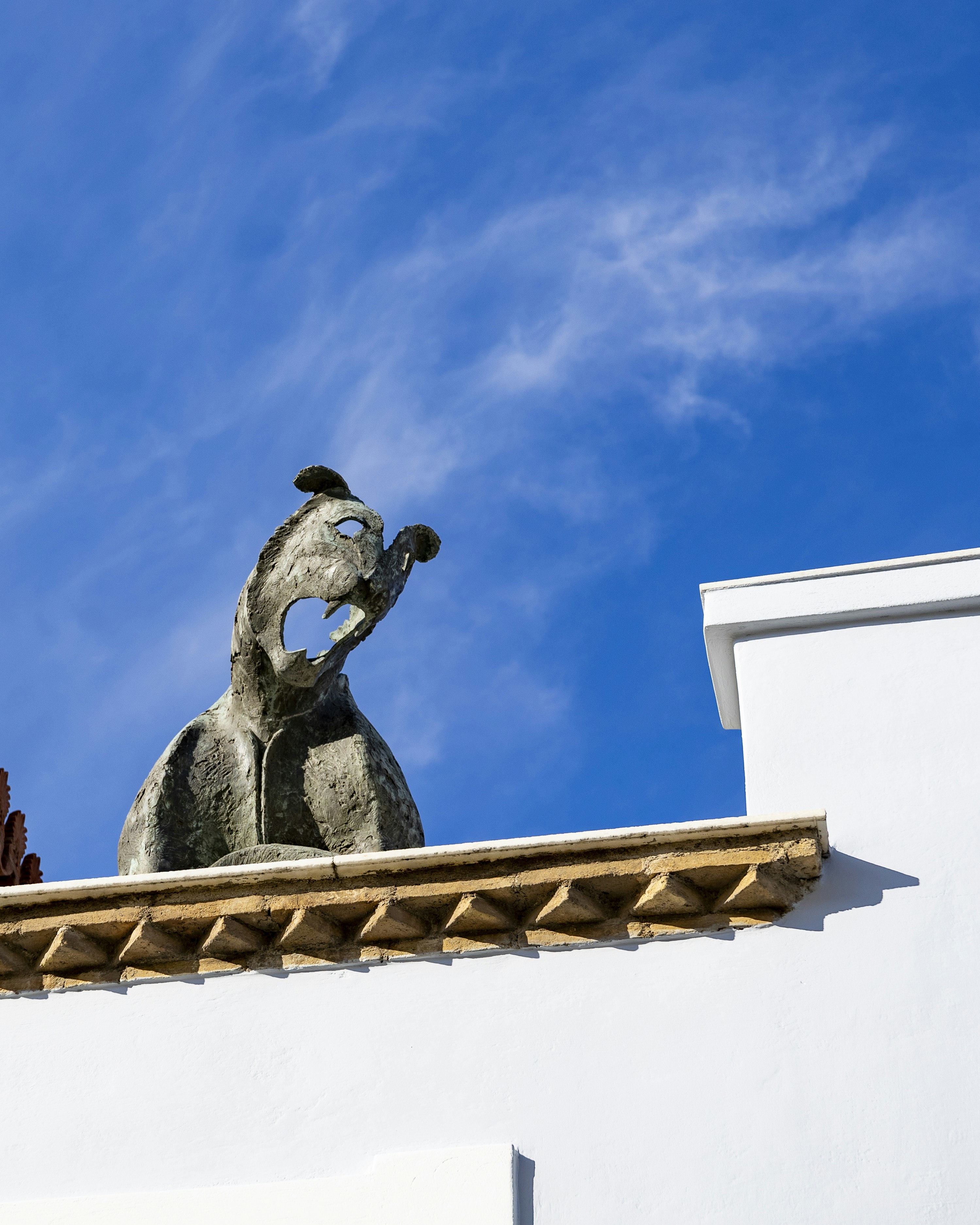 Keeper of the Roof: Weathered Stone Figure Against a Cobalt Sky
