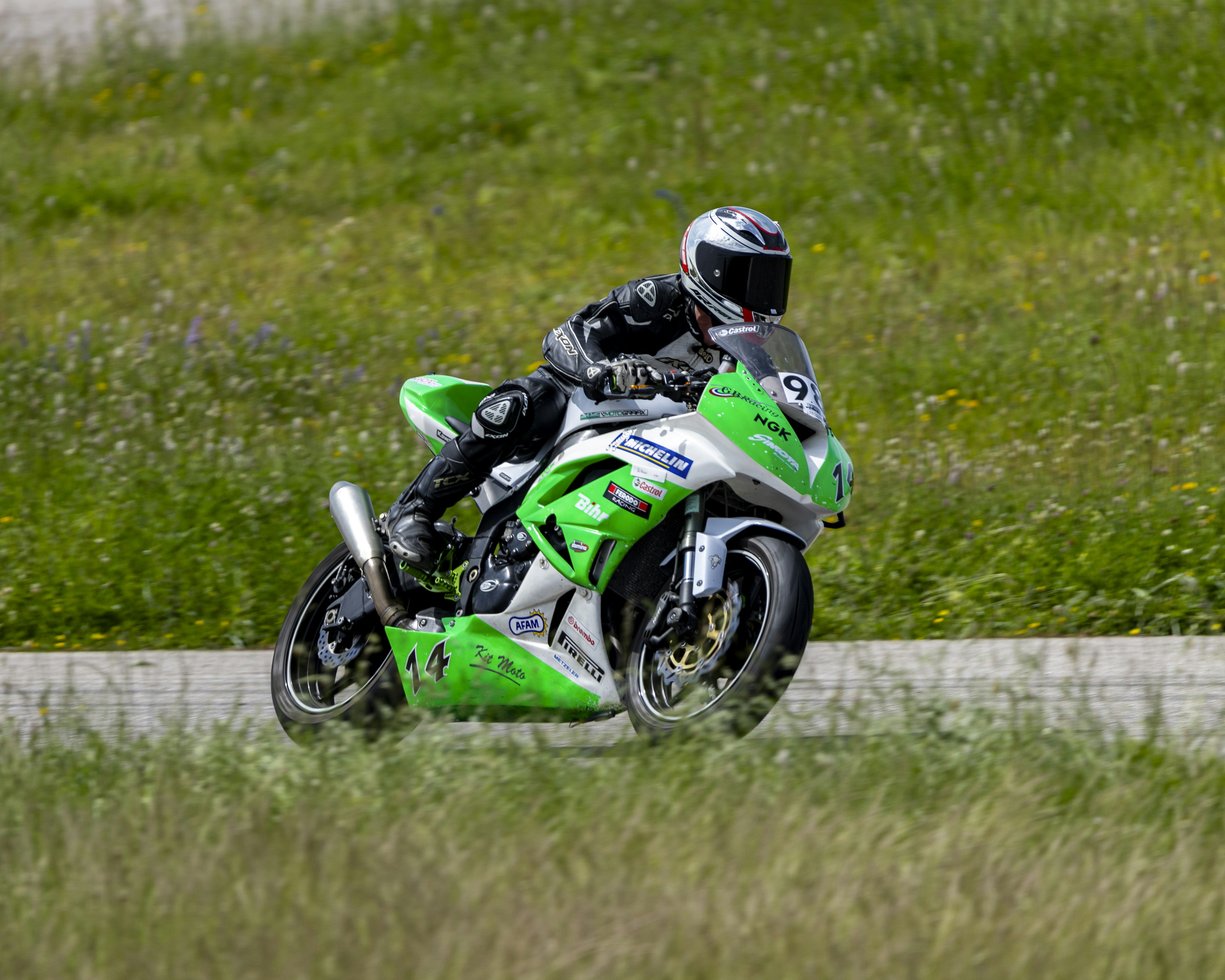 Neon-green Sprint: A race motorcycle leans through a sunlit curve