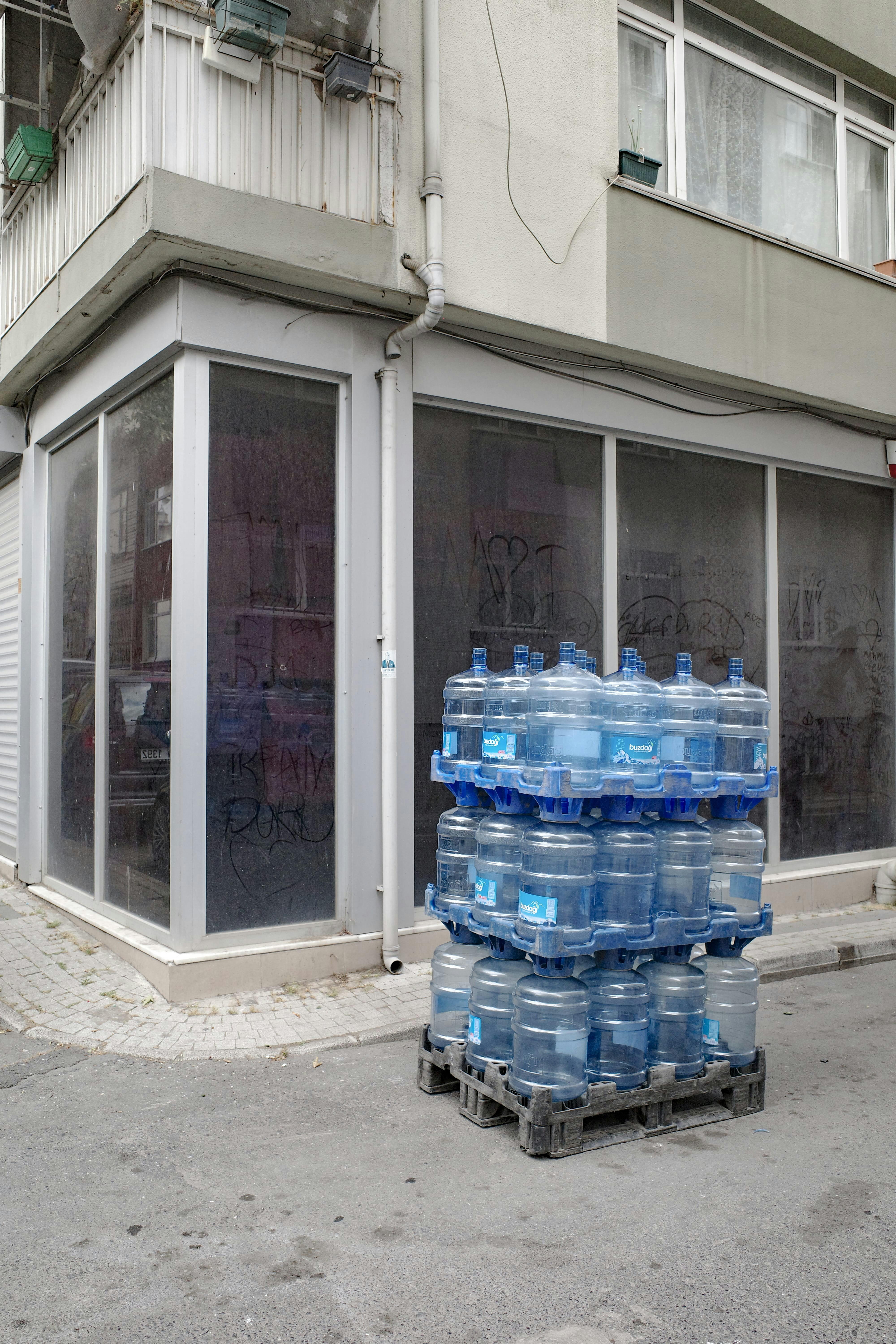 A stack of water bottles sitting in front of a building photo – Free ...