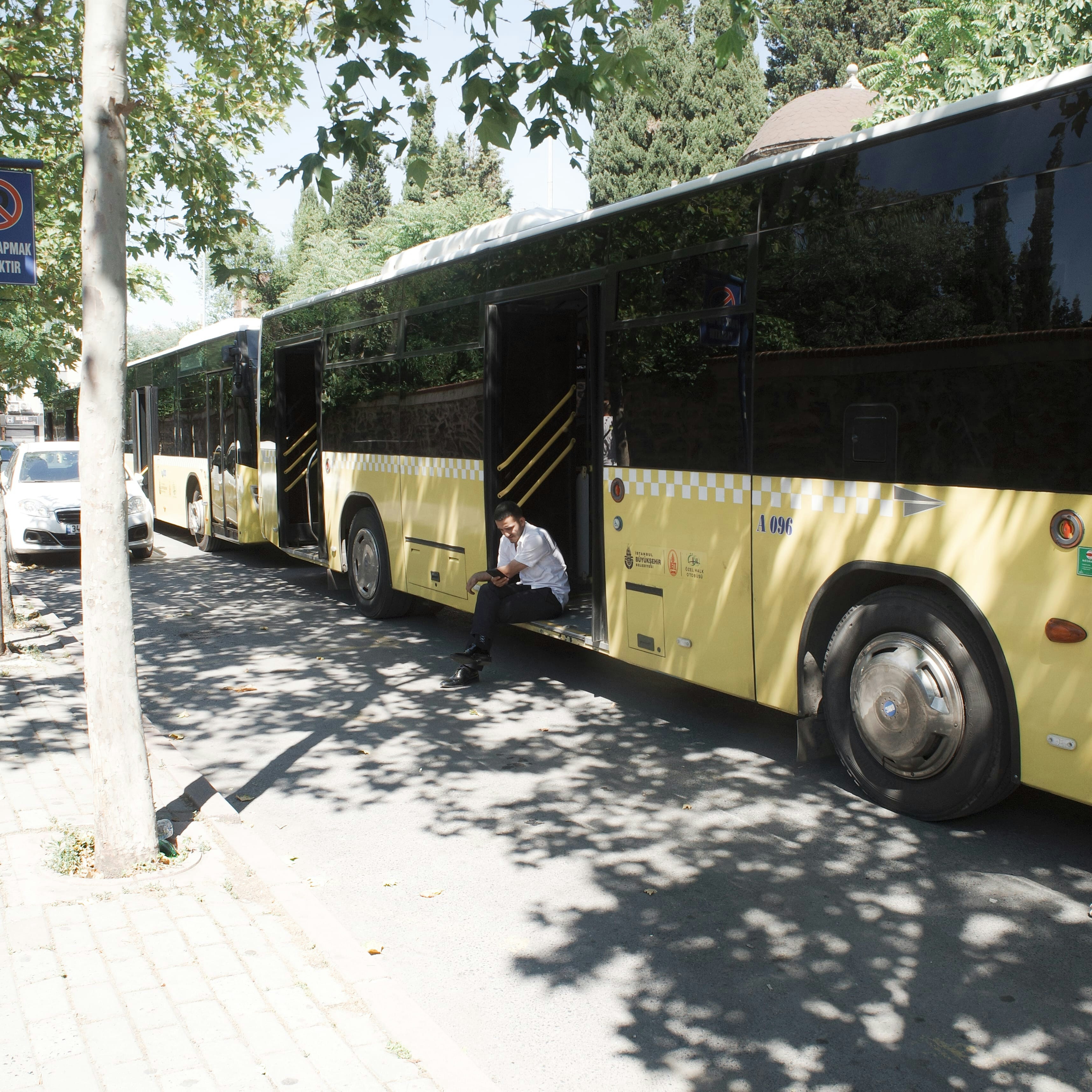 A man sitting on the side of a yellow and black bus photo – Free Car ...