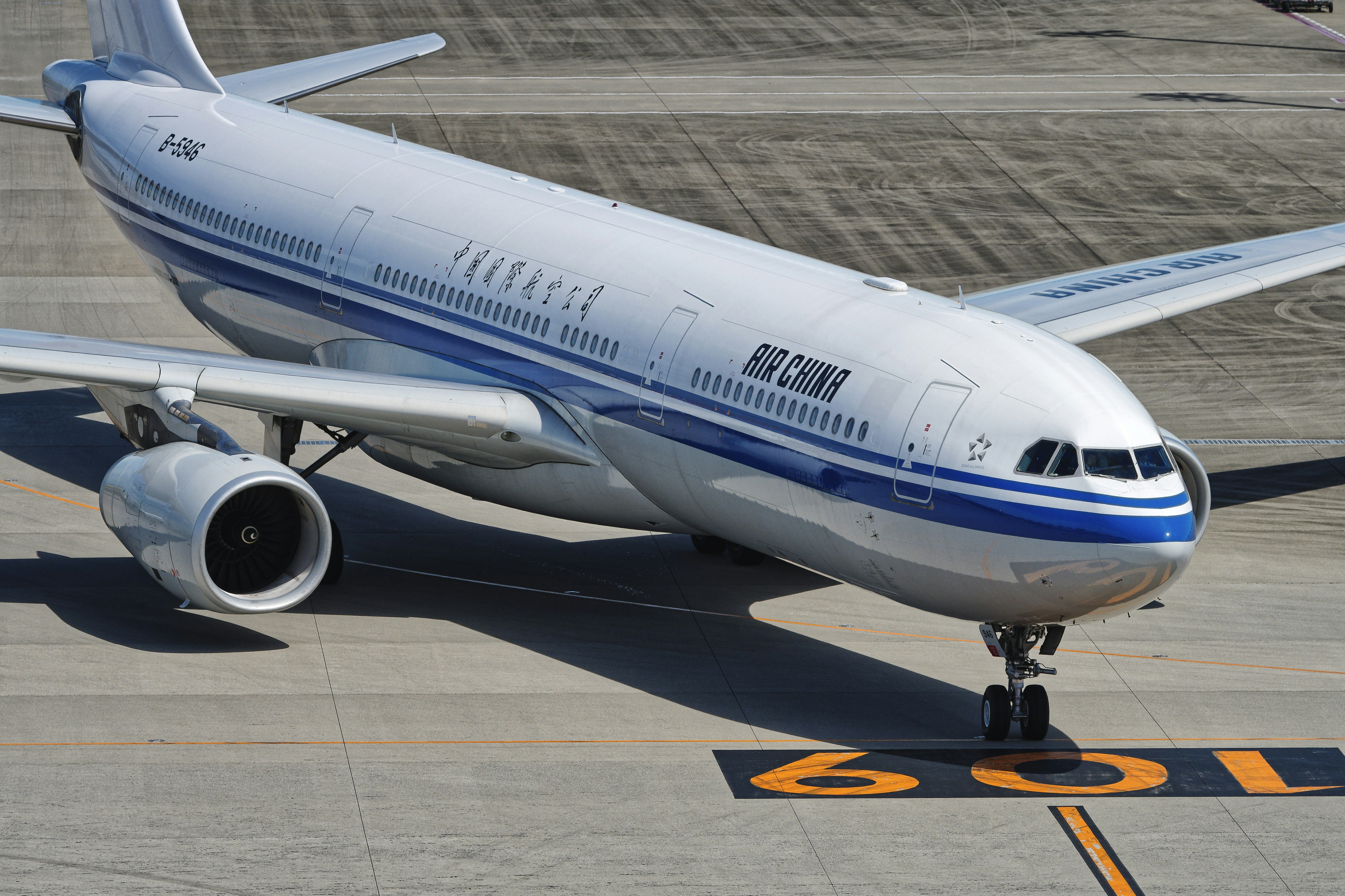Air China wide-body taxi: bold blue stripe crossing the gate
