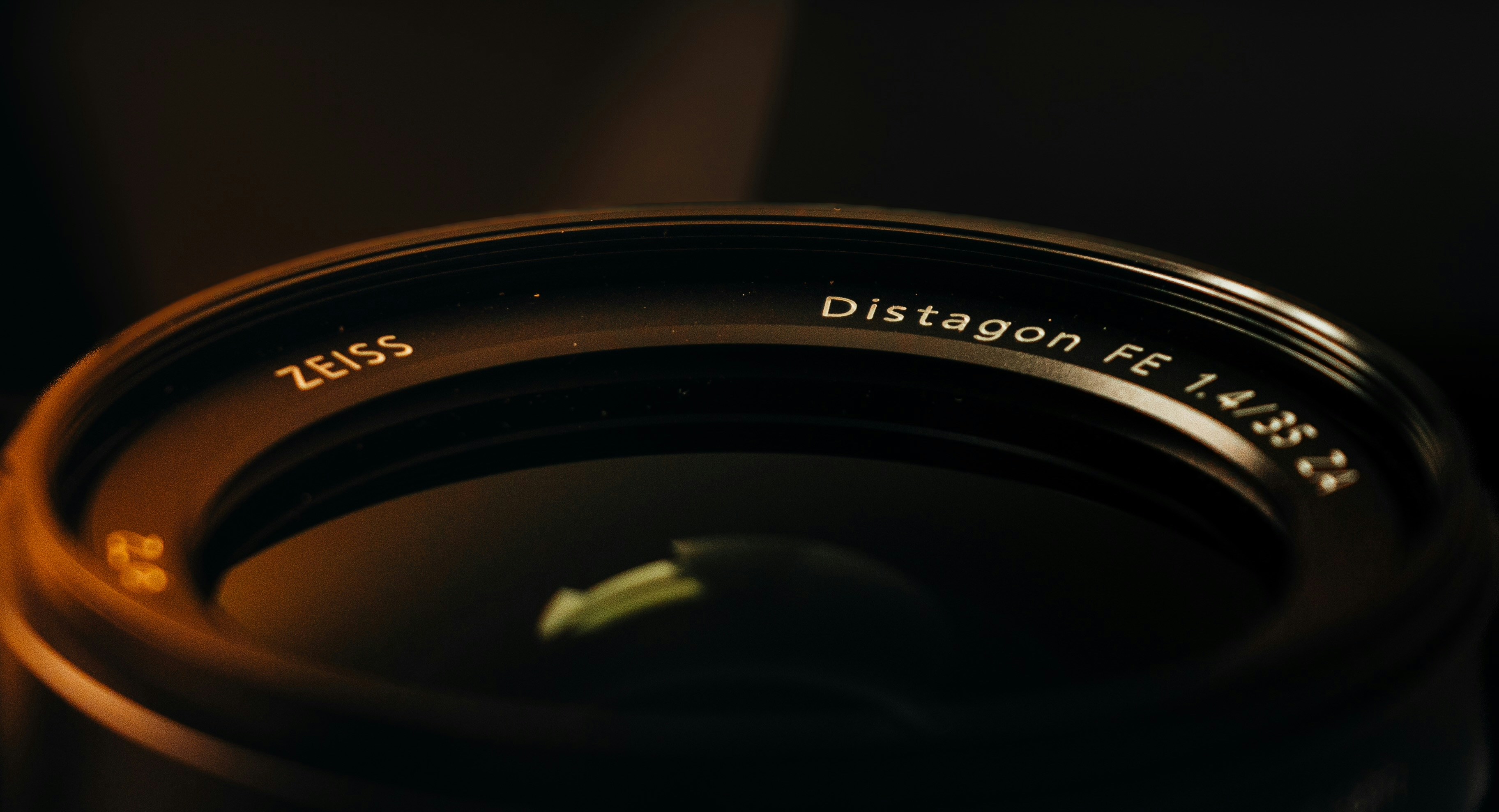 Close-up of Zeiss Distagon 35mm lens with detailed markings in warm lighting.