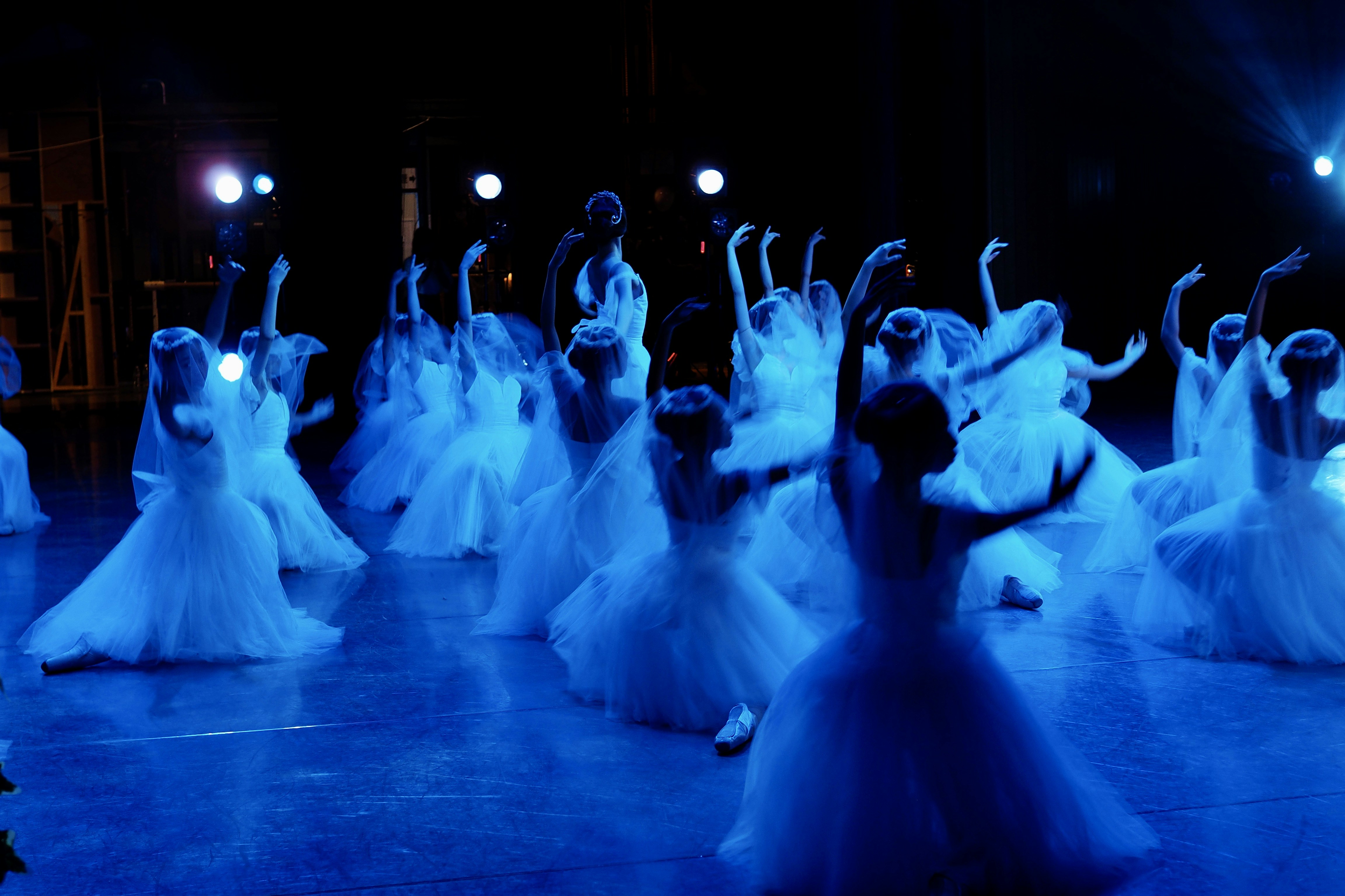 A group of people dressed in white dancing on a stage photo – Free ...