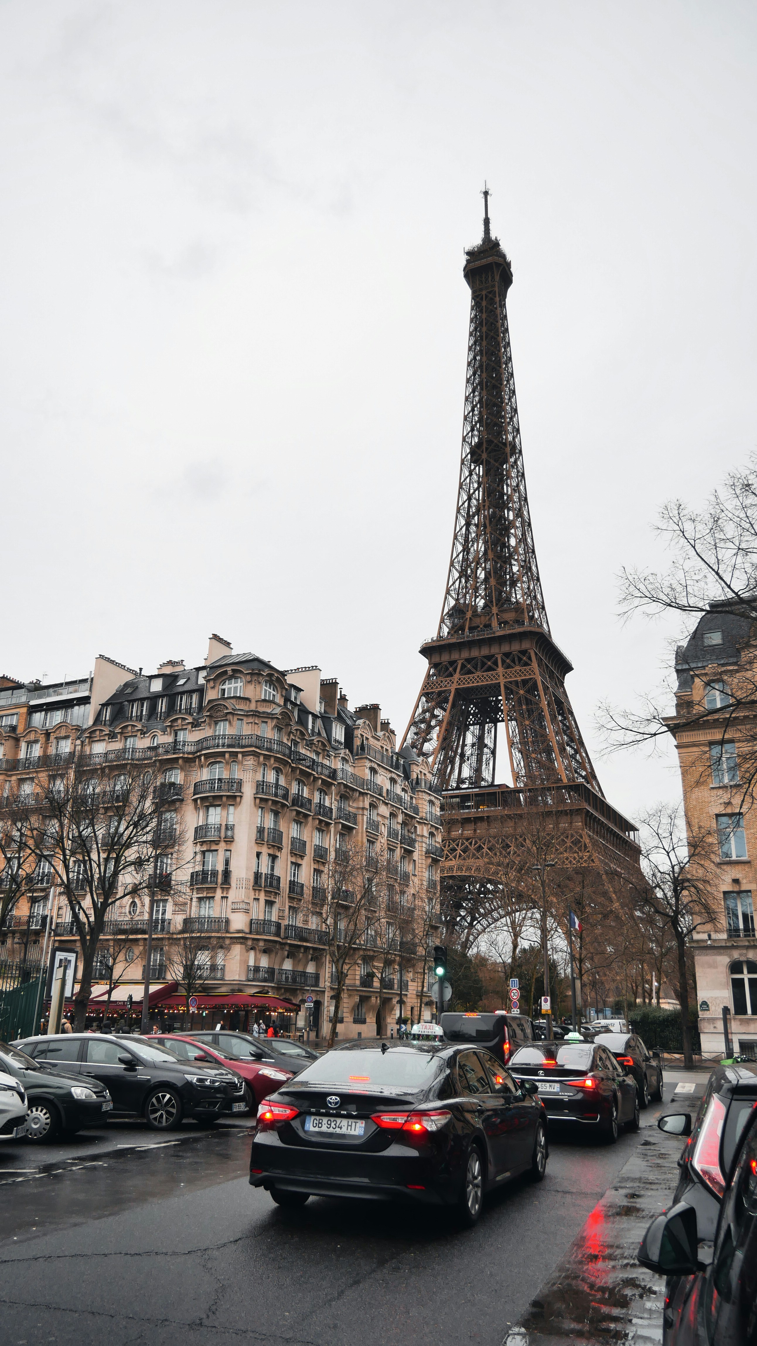 Crossroads Beneath the Iron Spine: Eiffel Tower Over a Parisian Street