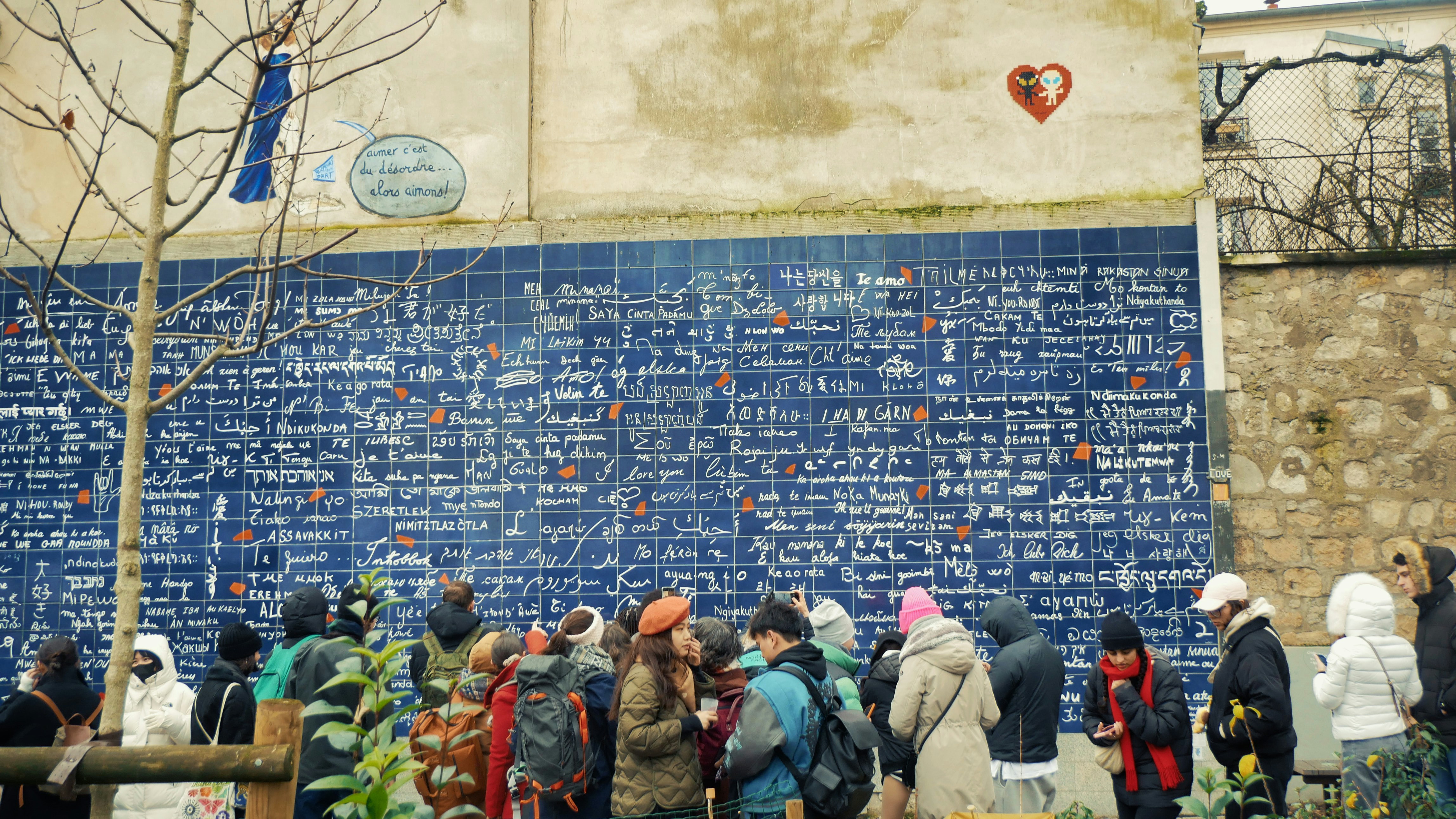 Whispers Beneath a Sea of Names: A Winter Crowd by a Blue Chalk Wall