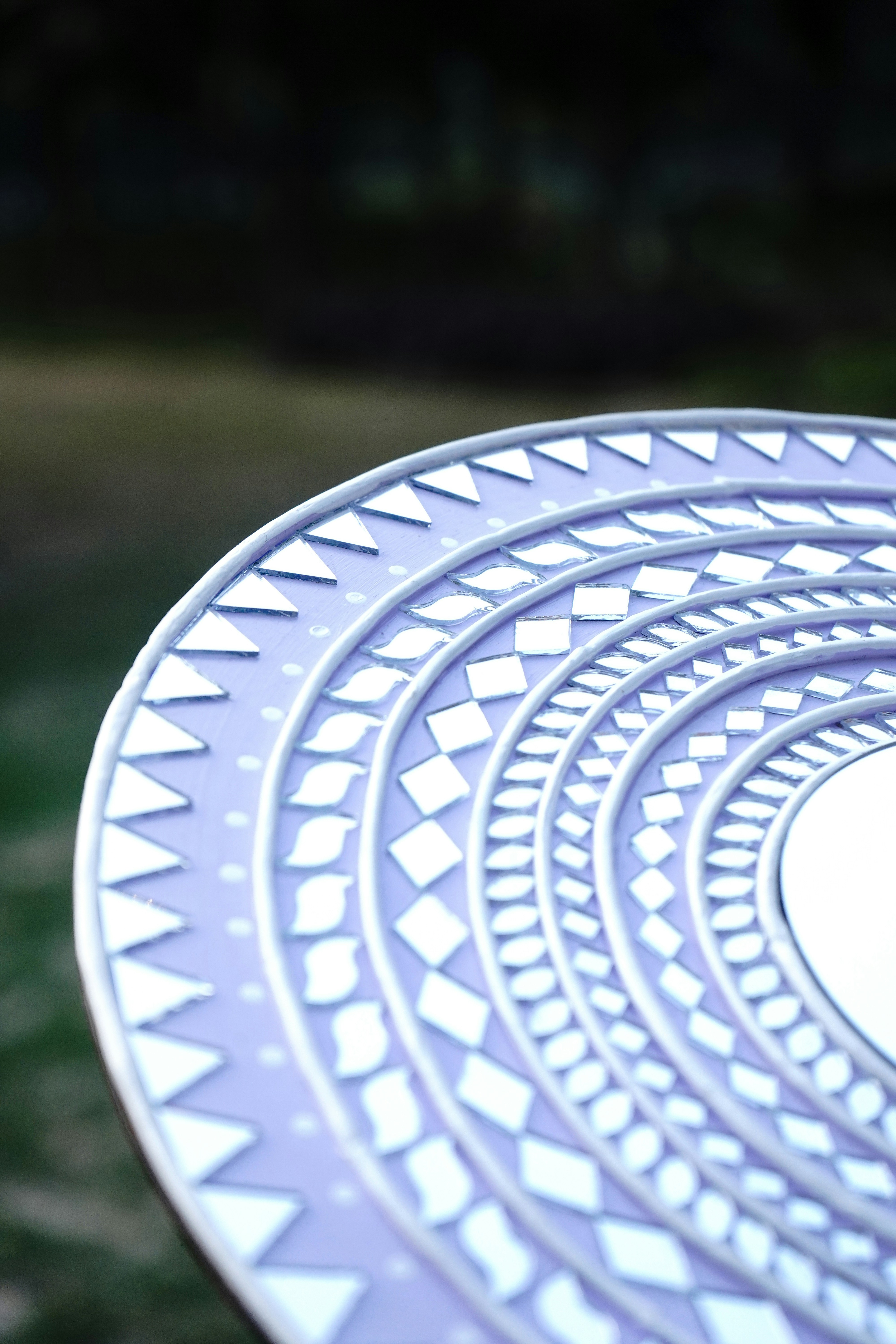 Mandala in White: Close-Up of a Geometric Plate with a Quiet Outdoor Backdrop