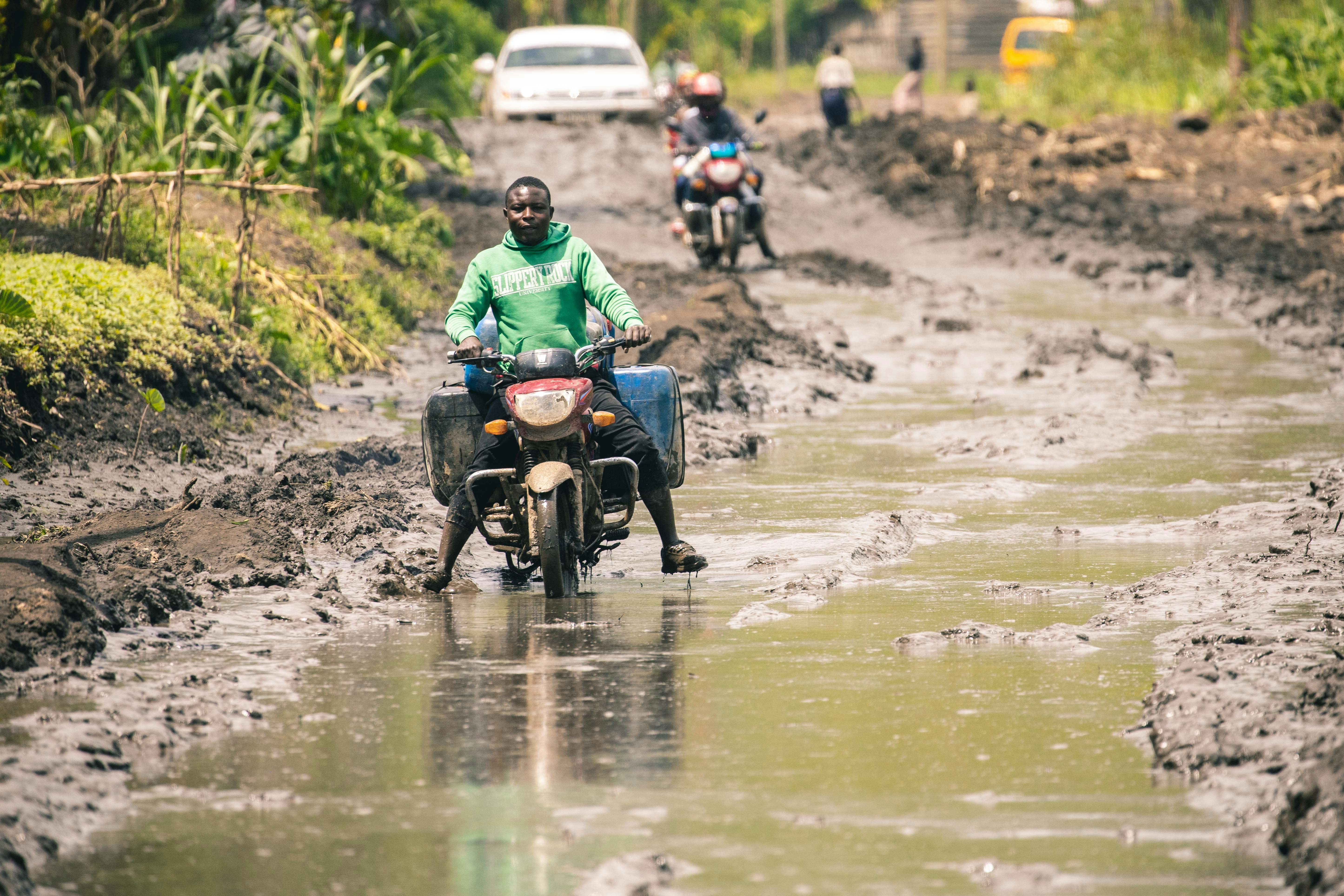 A man riding a motorcycle down a muddy road photo – Free Bweremana ...