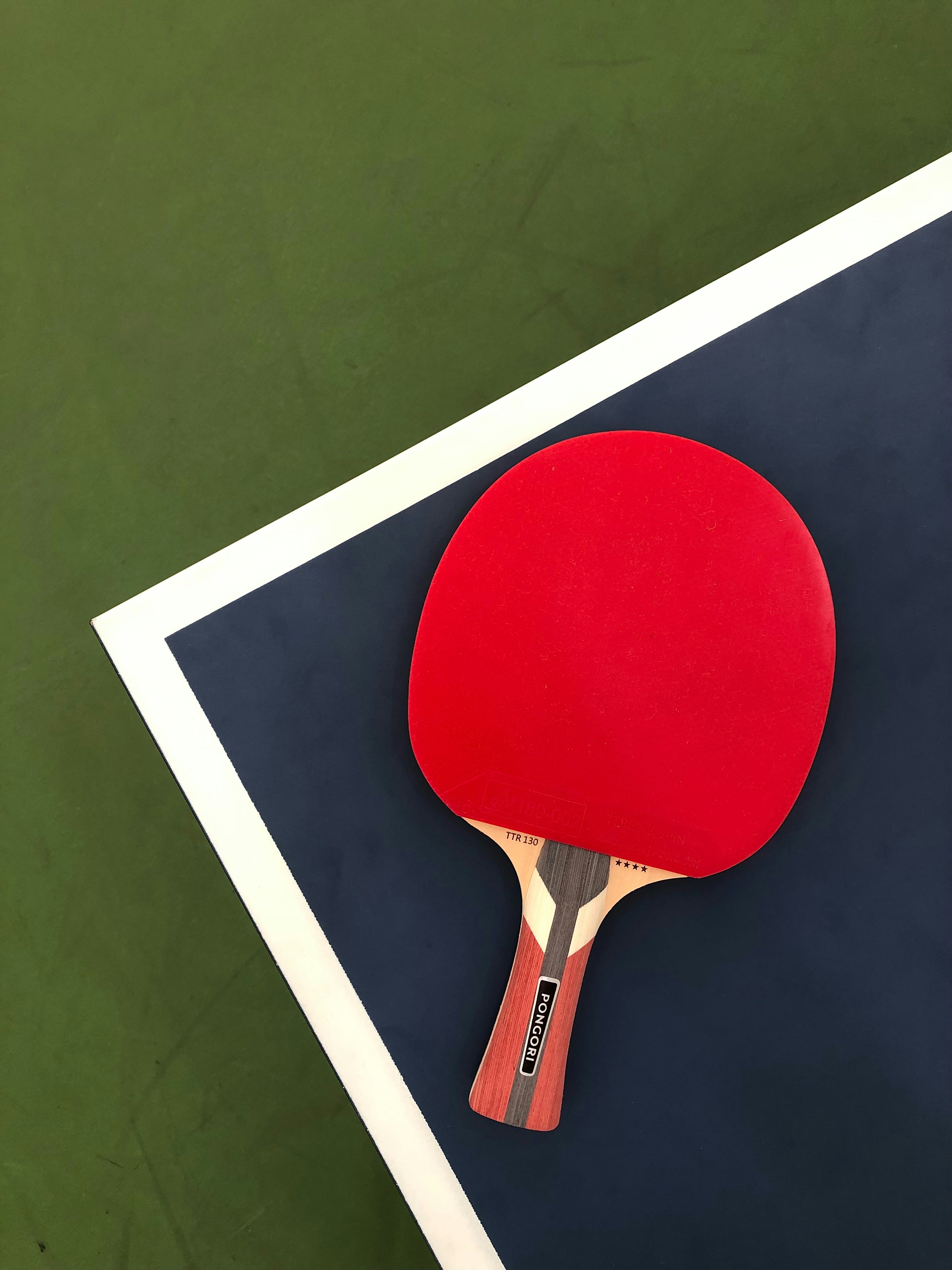 A ping pong paddle resting on top of a blue and green table photo ...