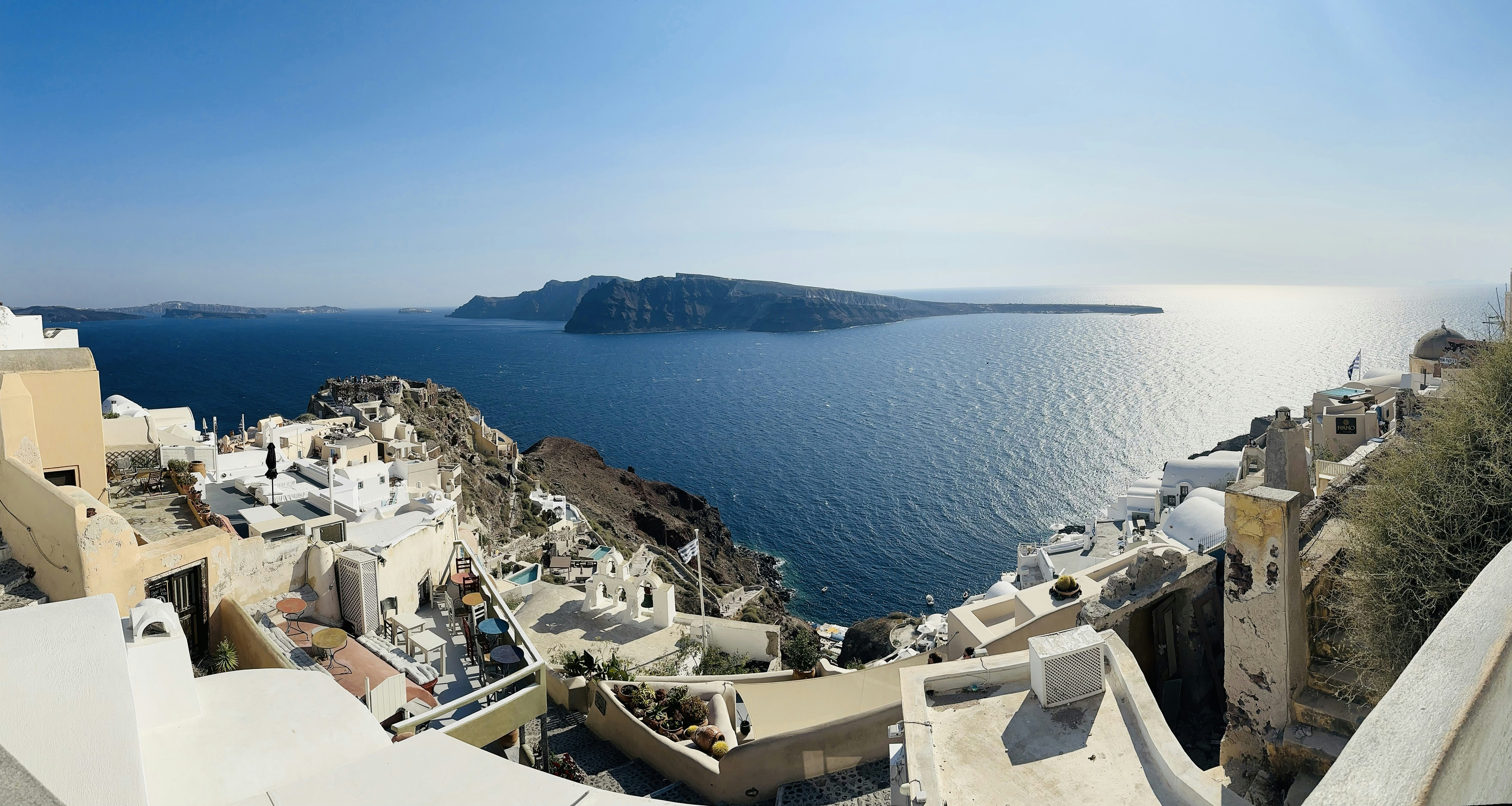 Whitewashed buildings of Santorini overlooking the deep blue Aegean Sea under a clear sky.