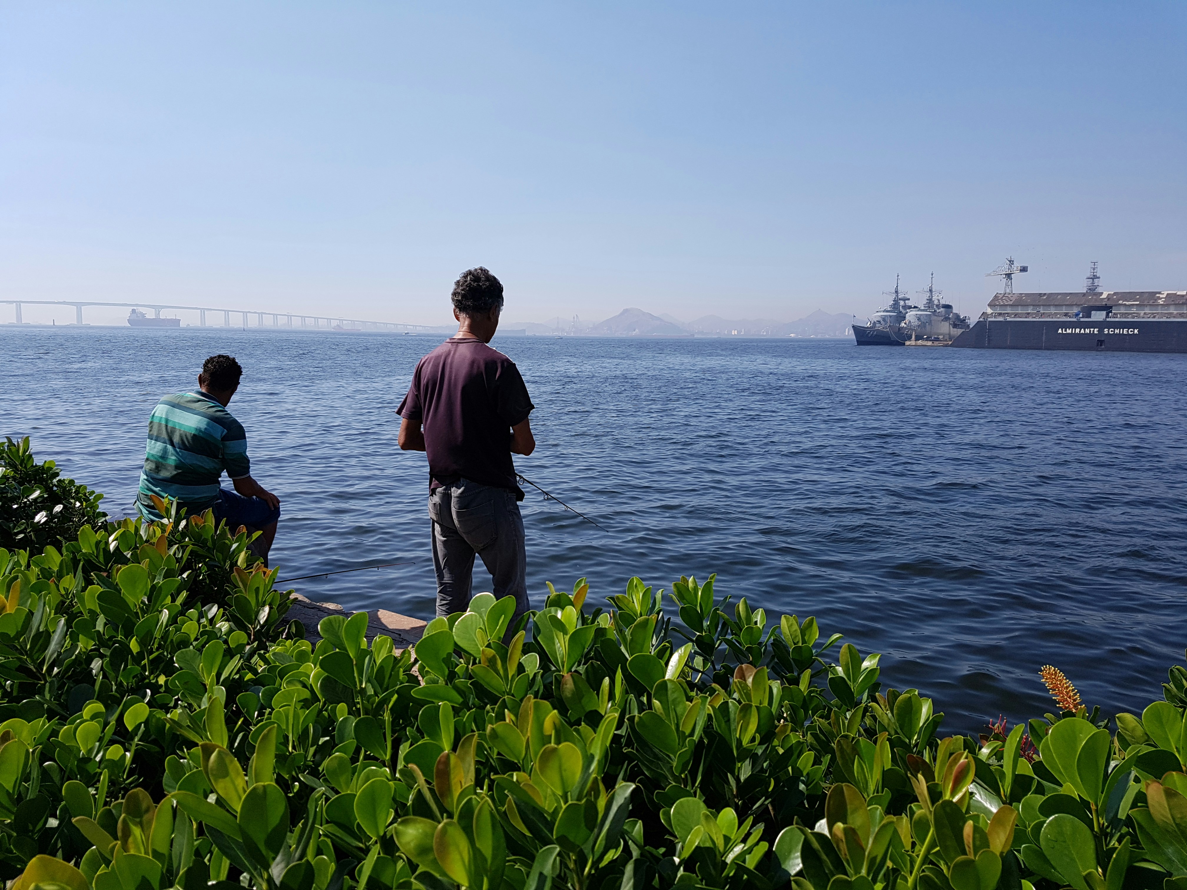 Pescadores pescam na região portuária do Rio de Janeiro | A couple of people that are standing by the water
