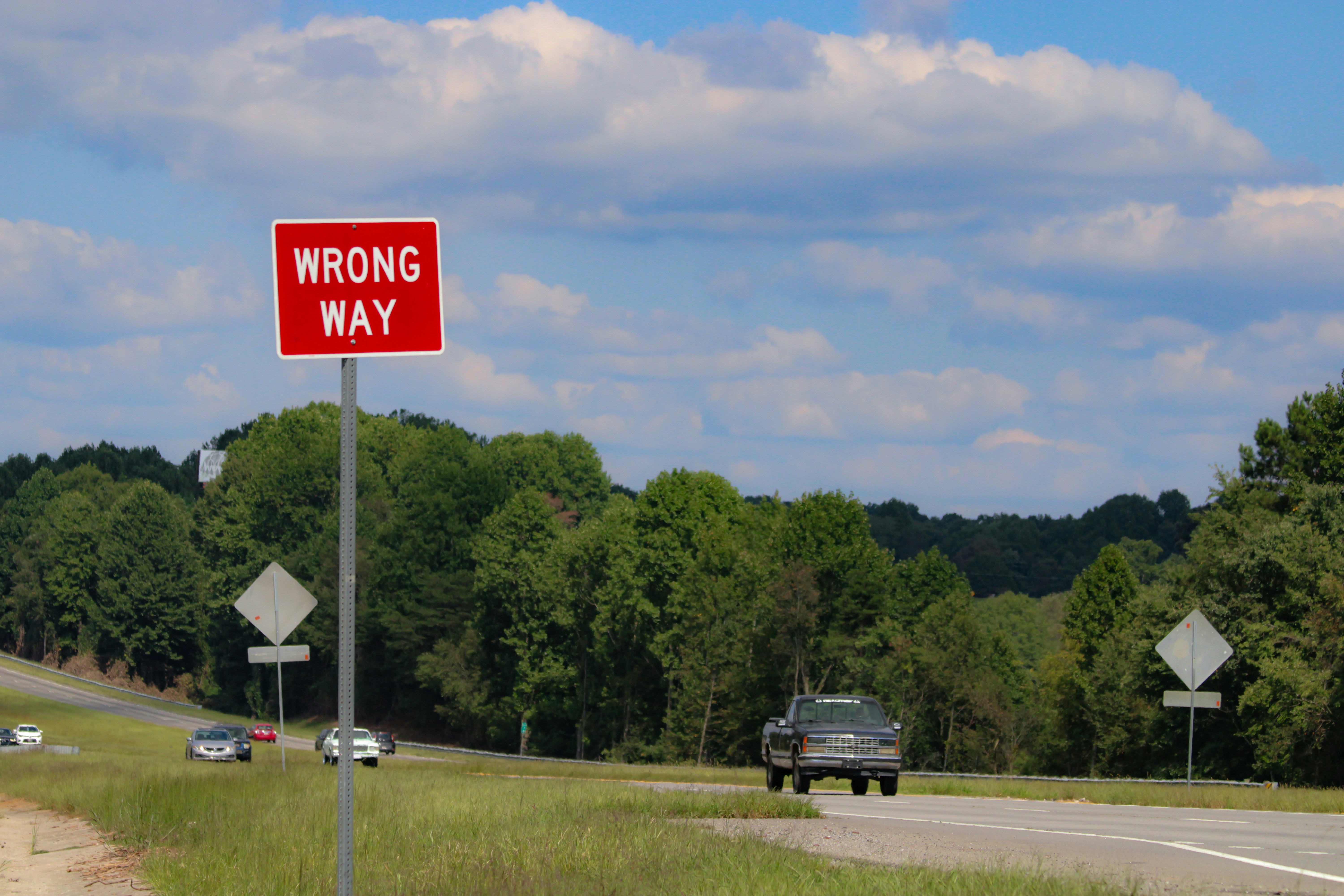 A red wrong way sign sitting on the side of a road photo – Free Summer ...