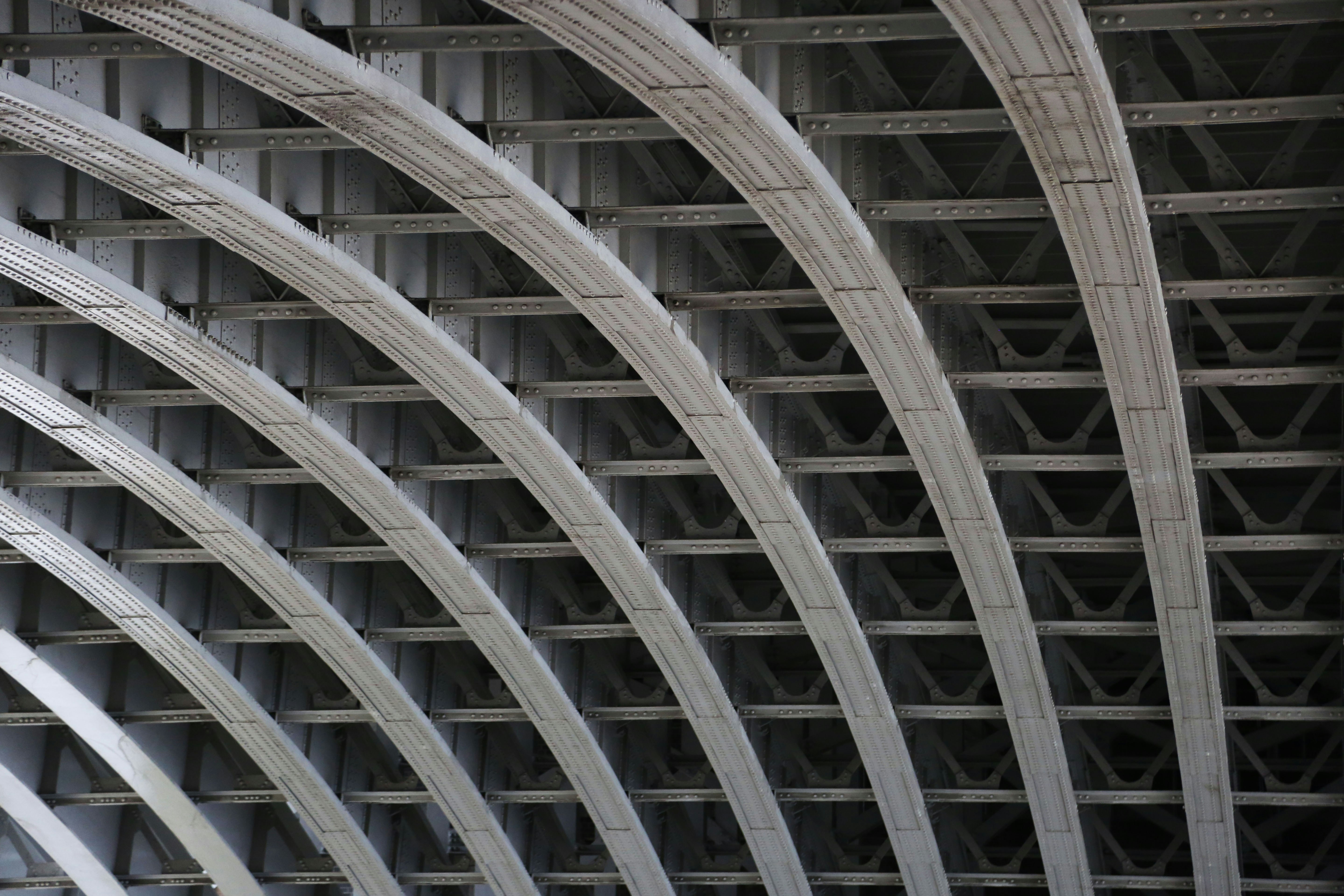 Intricate metal structure featuring repetitive arches and geometric patterns in cool gray tones.